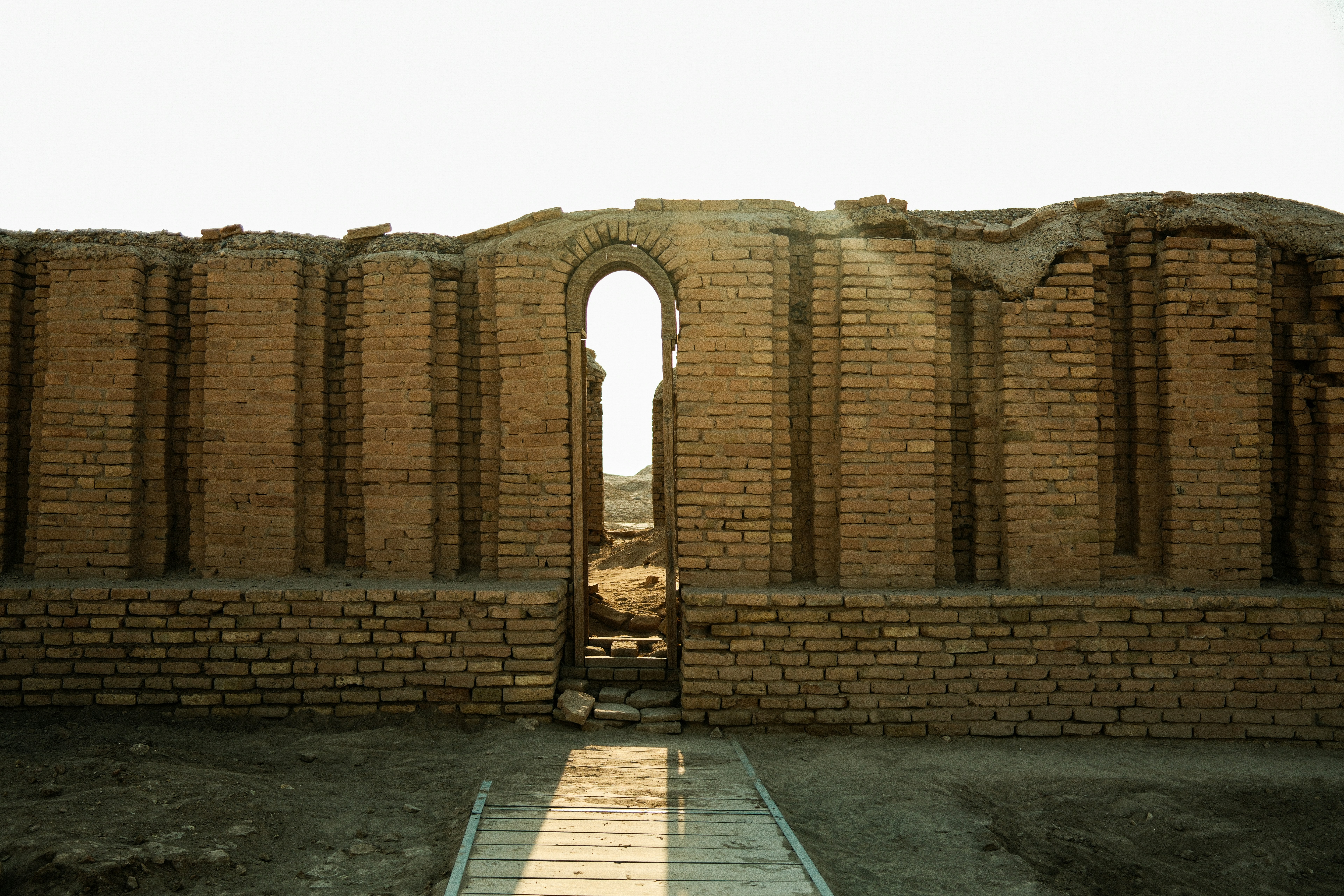 Archway at the Threshold: Sunlit Ruins Framed by a Wooden Path