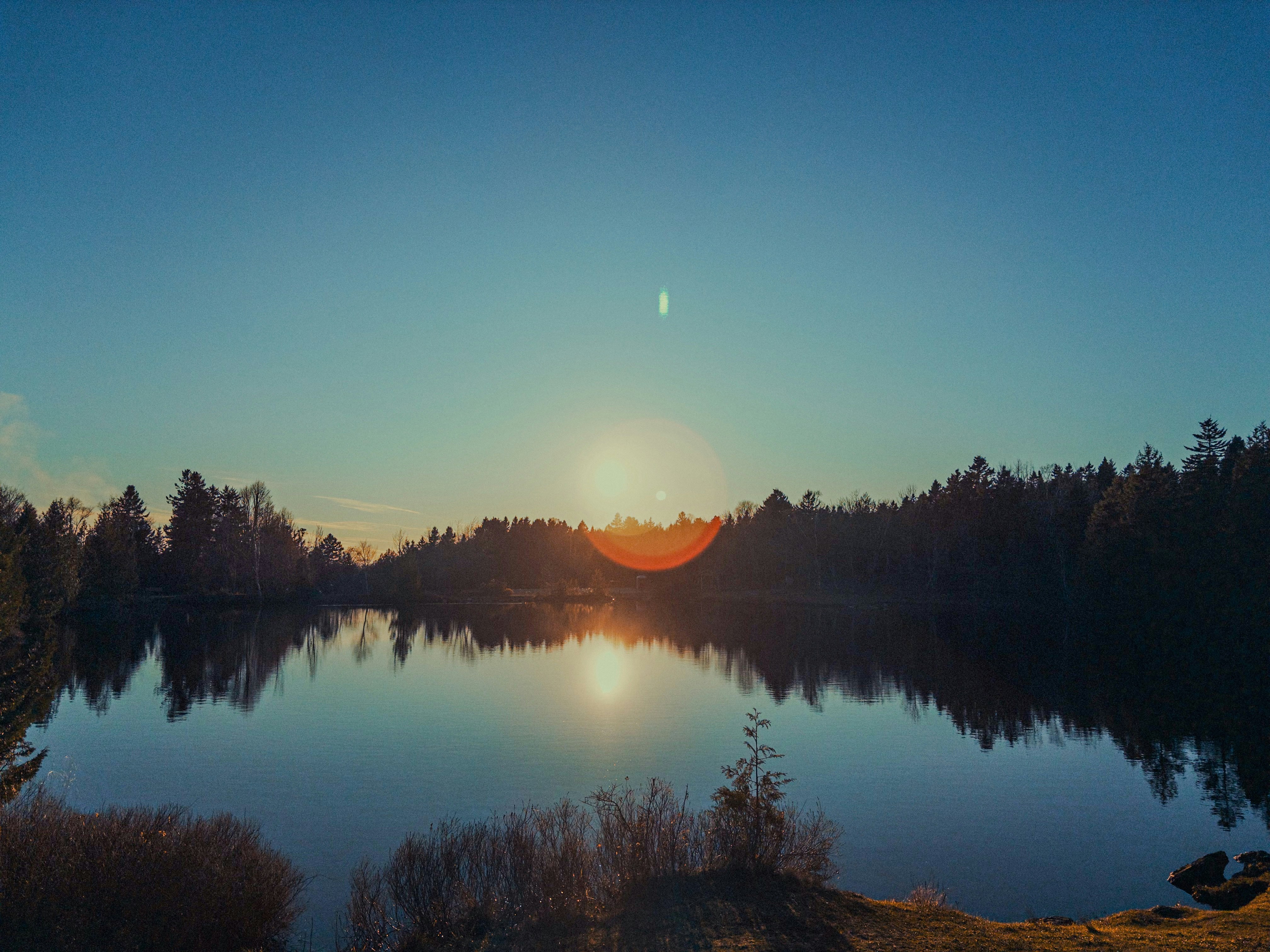 Sunset over a calm lake with trees
