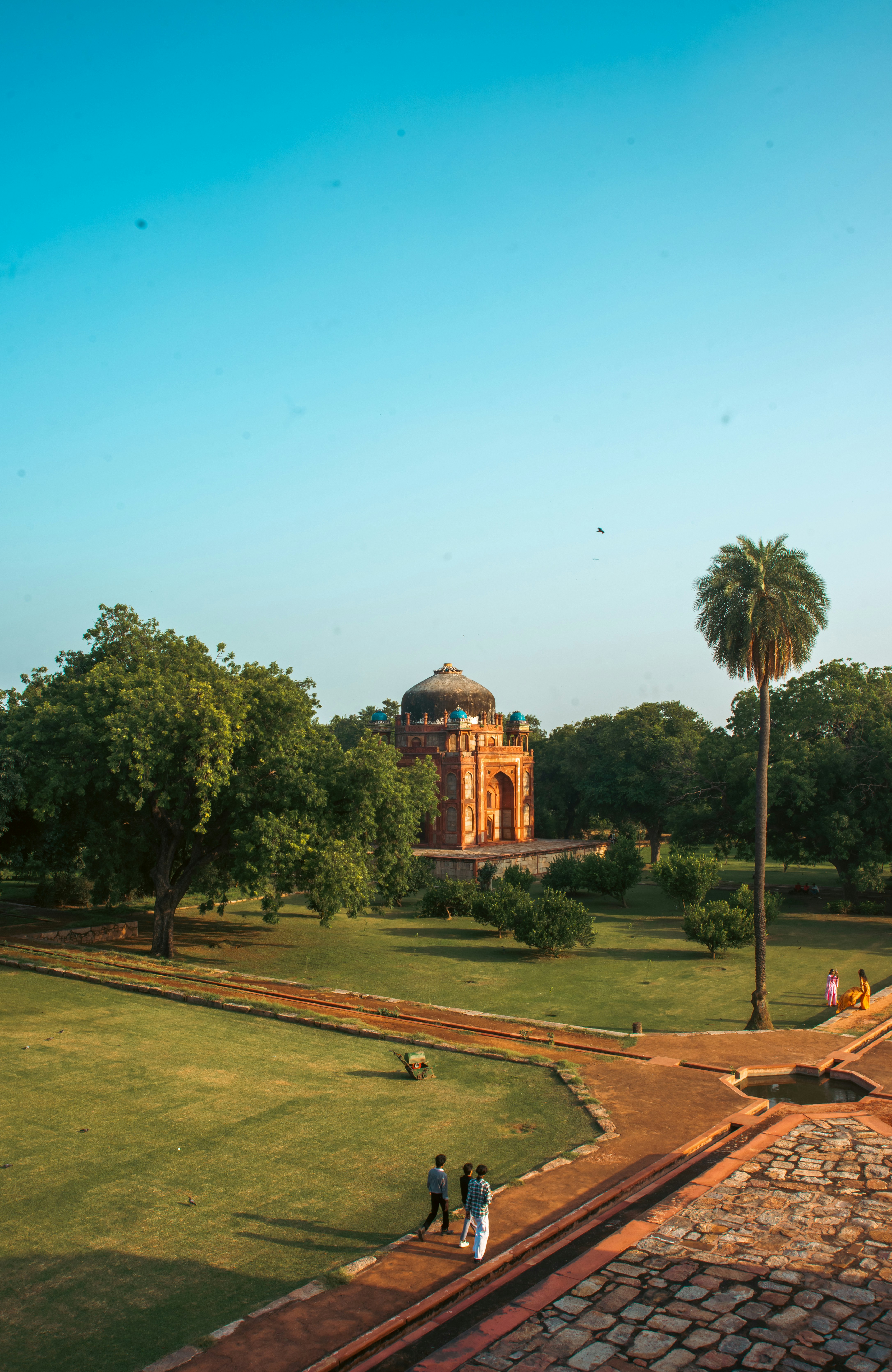Located in the southeast quadrant of Humayun's Garden Tomb, the Barber's Tomb (Nai ka Gumbad) is a striking red and gray sandstone mausoleum. Standing on a square plinth, the symmetrical structure features four corner chhatris and a central dome resting on an octagonal drum. The design mirrors the main tomb’s grandeur, utilizing squinch arches, intricate geometric jali screens, and star-shaped spandrel decorations. Notable details include a stone mihrab with a Sultanate-style hanging-bell motif. Inside, two anonymous cenotaphs rest beneath the high dome.