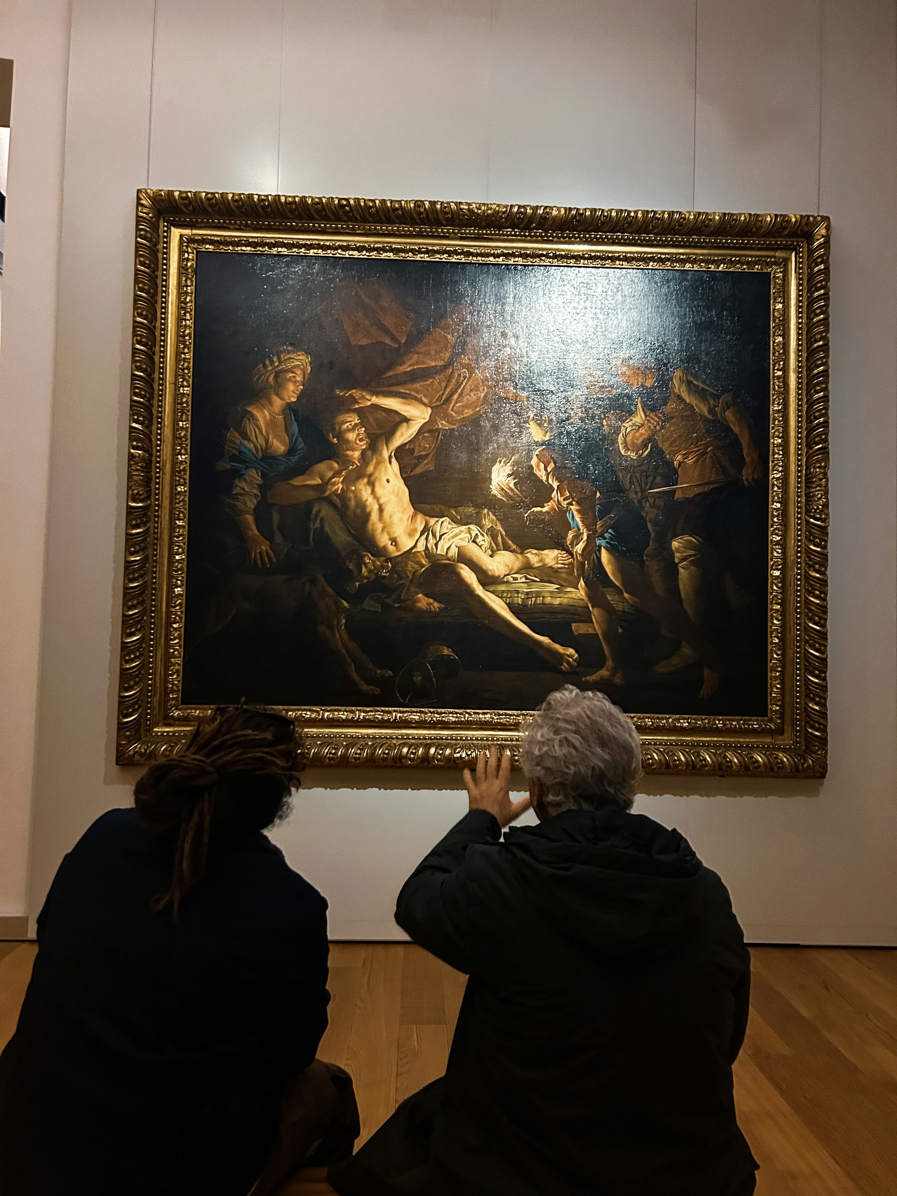 People observe a painting in a museum
