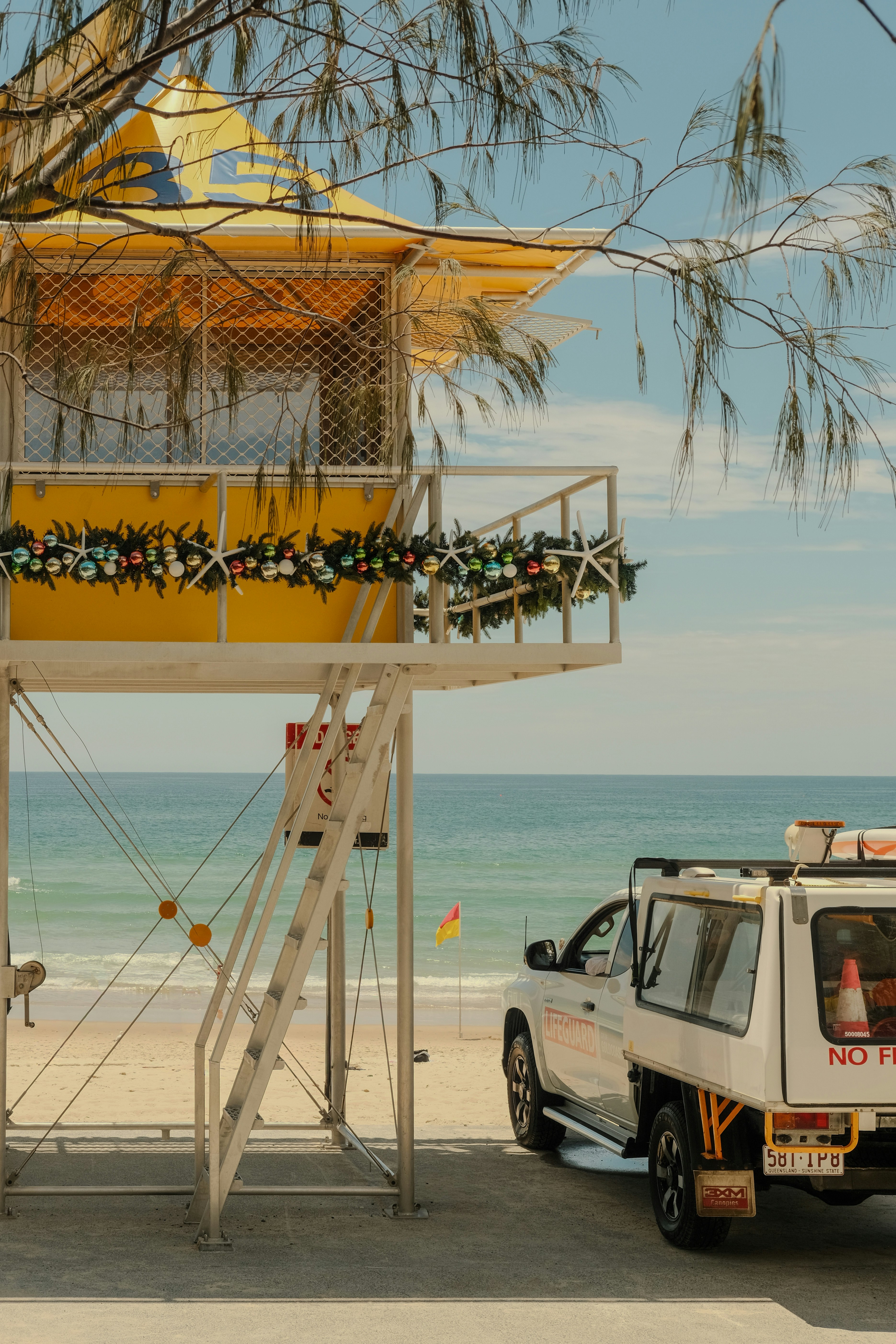 Yellow Lifeguard Tower Draped in Flowers Along a Calm Atlantic Beach
