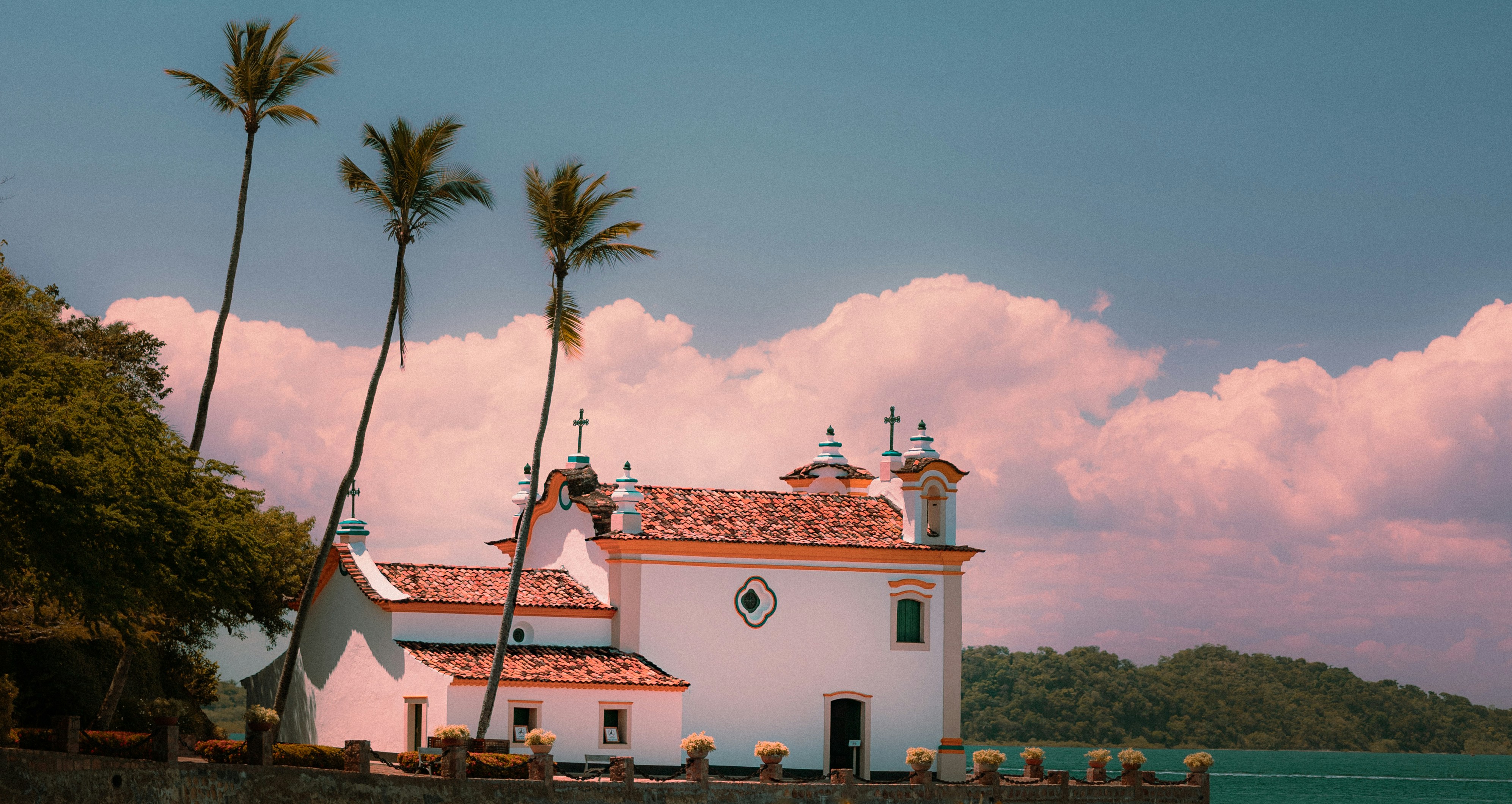Palm-Framed Chapel by Turquoise Sea Under Coral Clouds