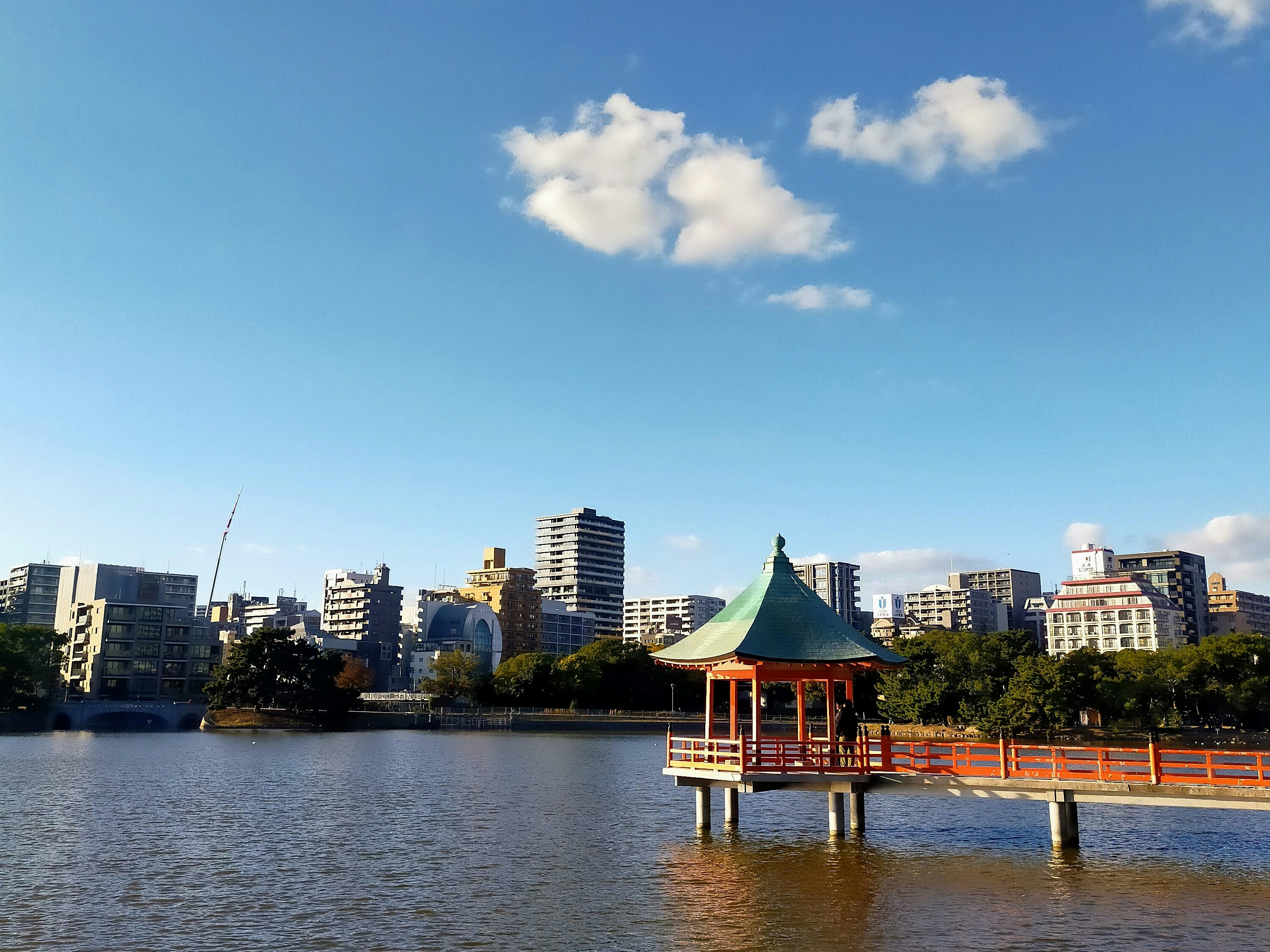 Pagoda structure on a lake with city skyline