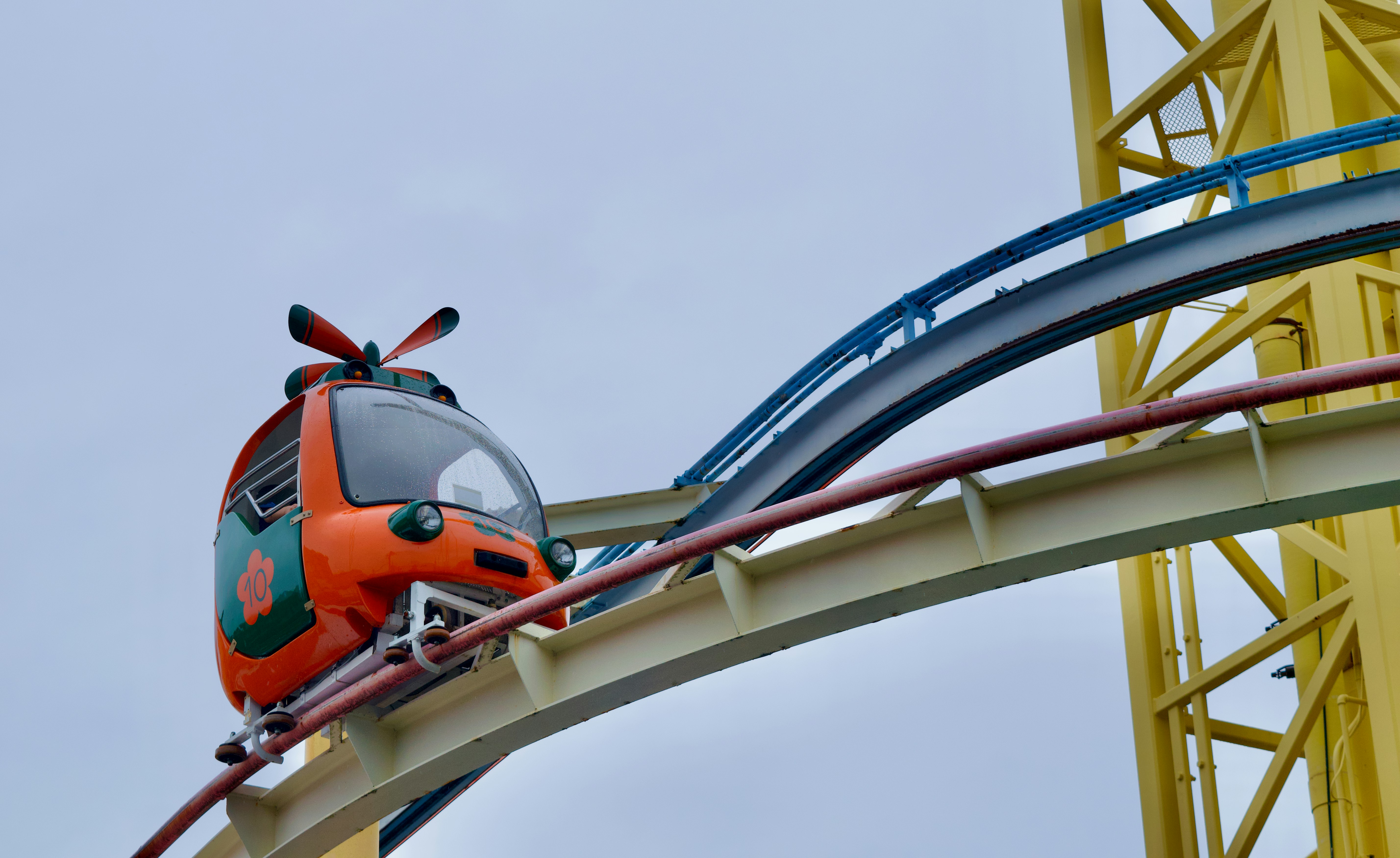 Hovering on the Curve: An Orange Helicopter on a Blue Roller-Coaster Arc