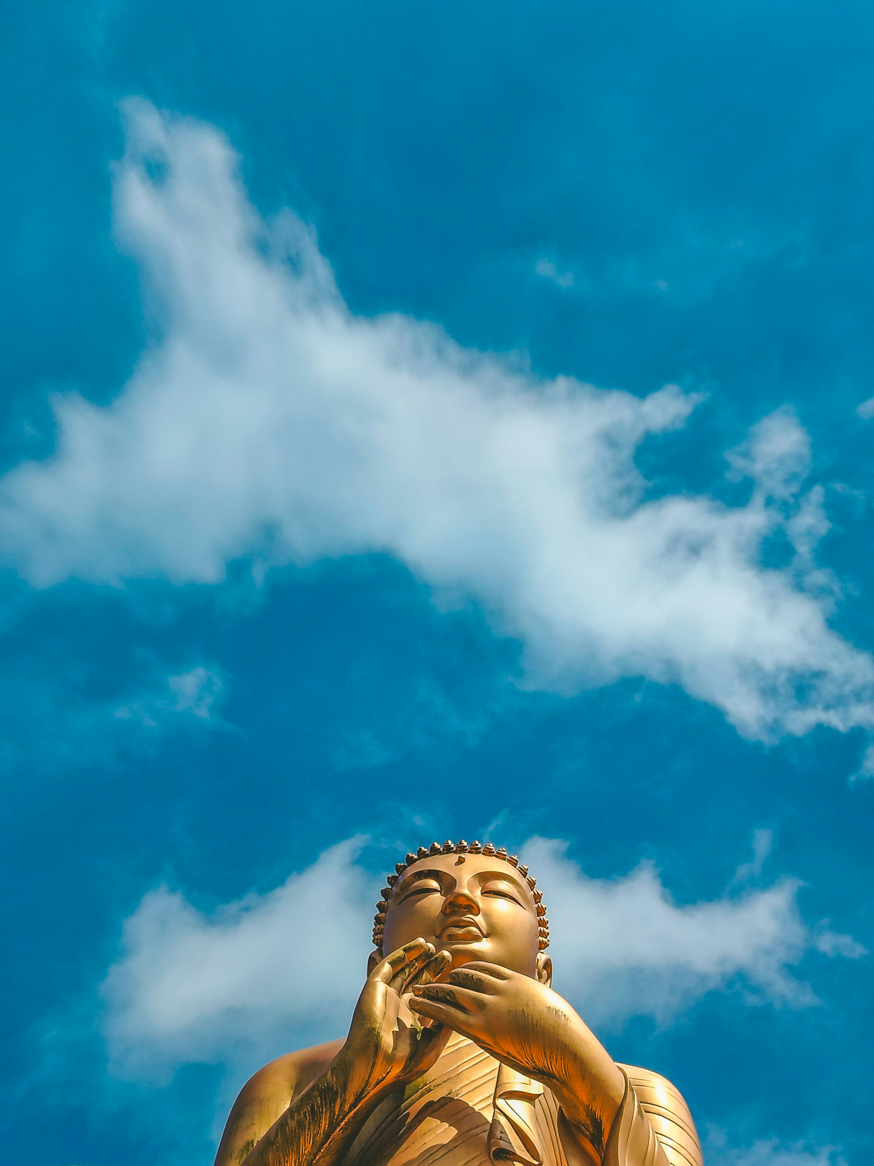 Golden buddha statue against a bright blue sky