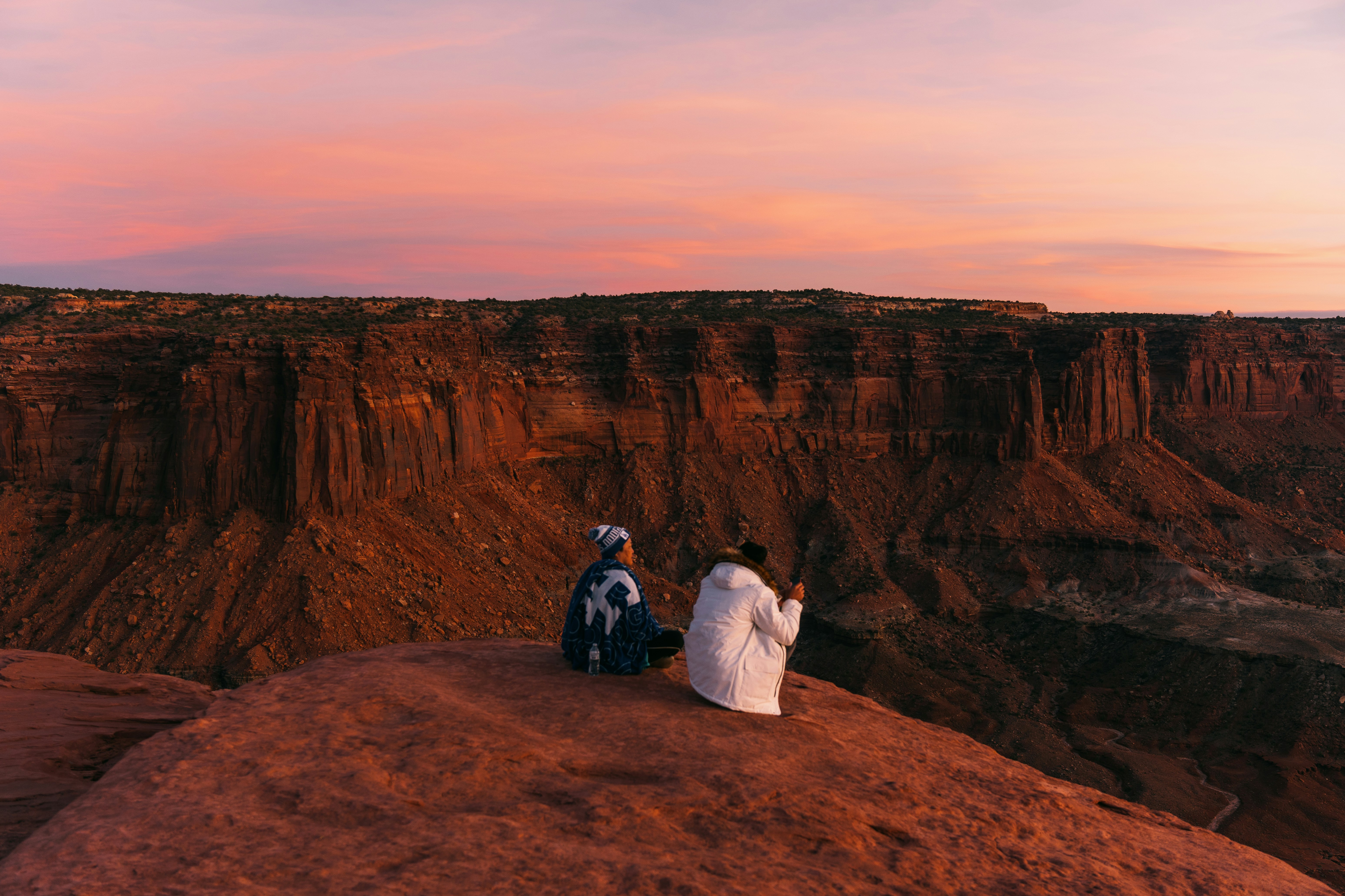 Dusk on the Rim: Two Travelers at the Edge of a Crimson Canyon
