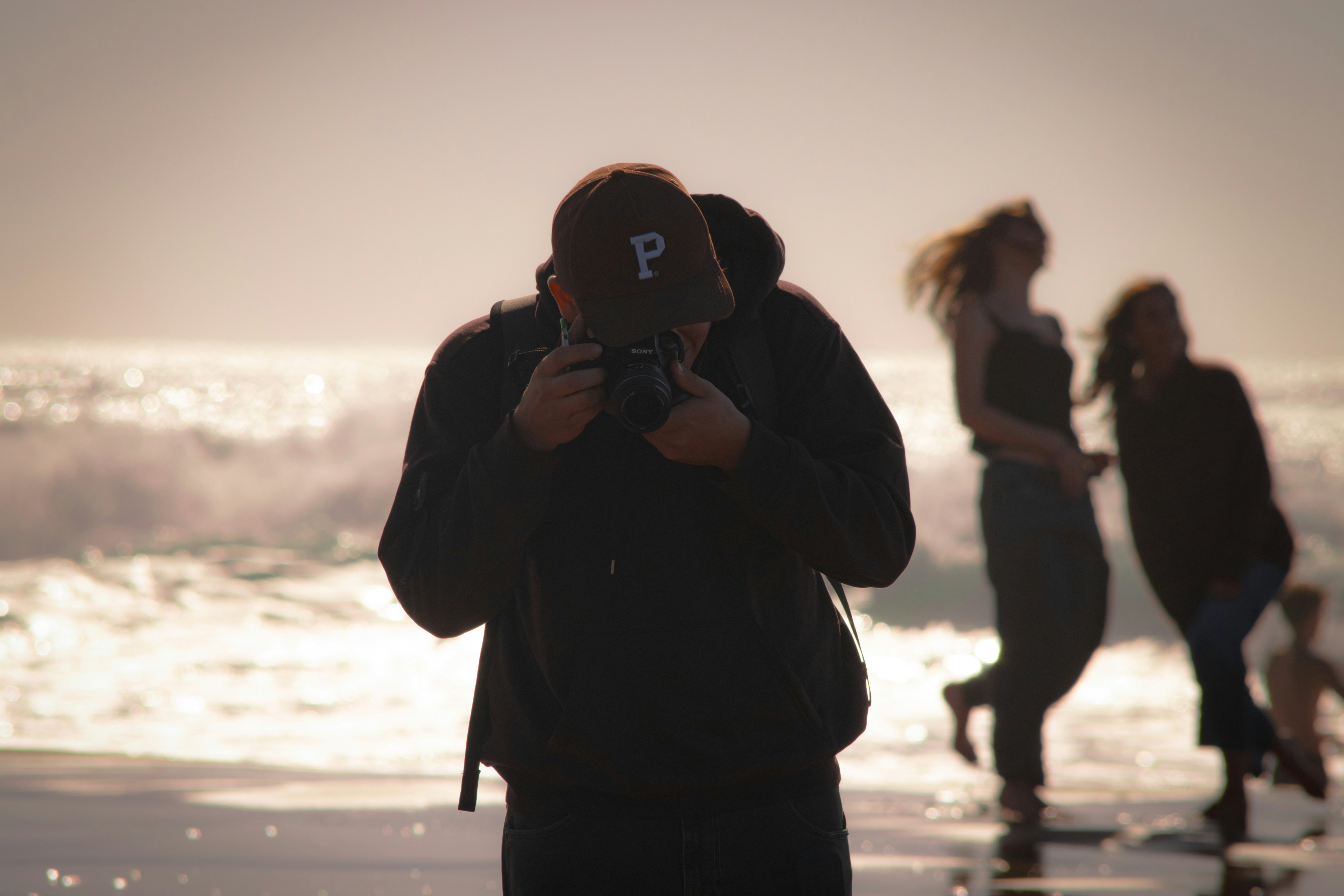 Golden Hour Silhouette: A Beach Photographer Framed by Wave and Light