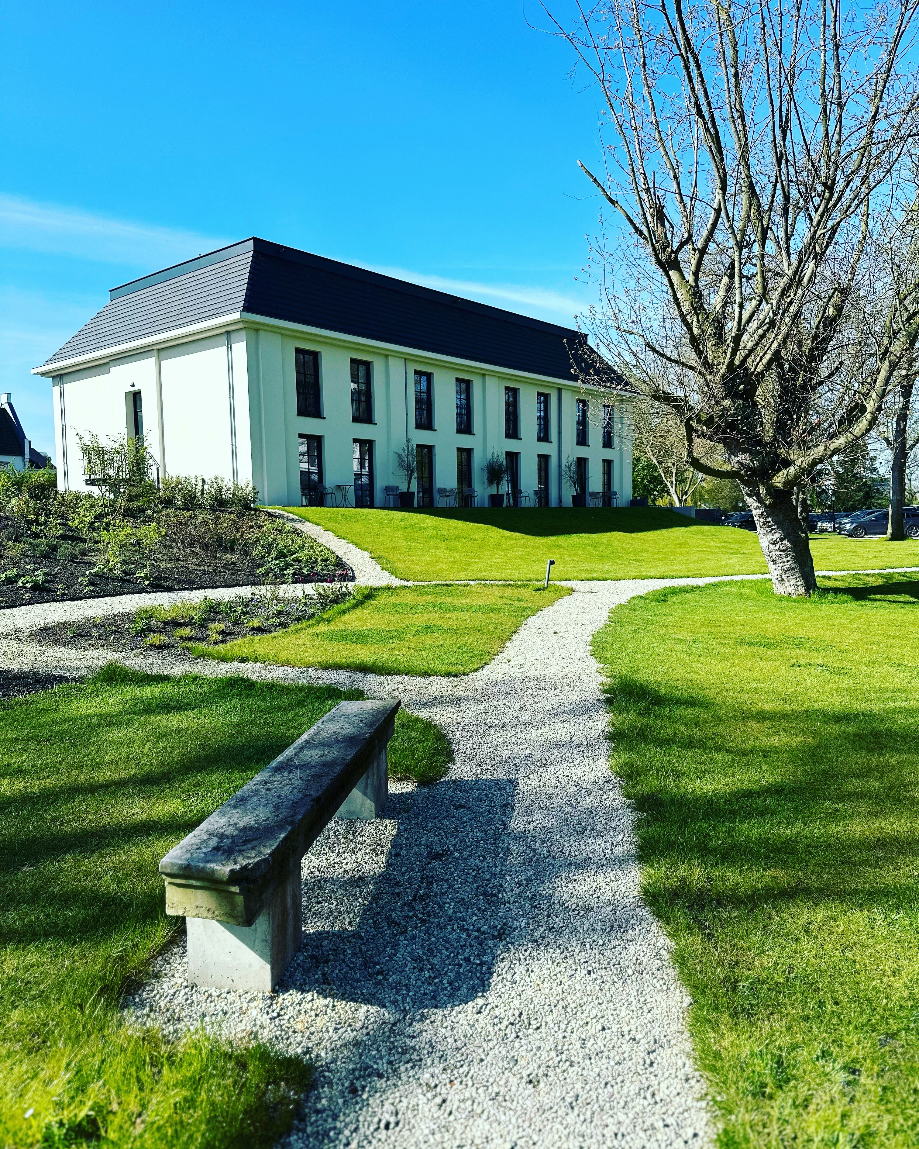 White building with a path and bench in a park.