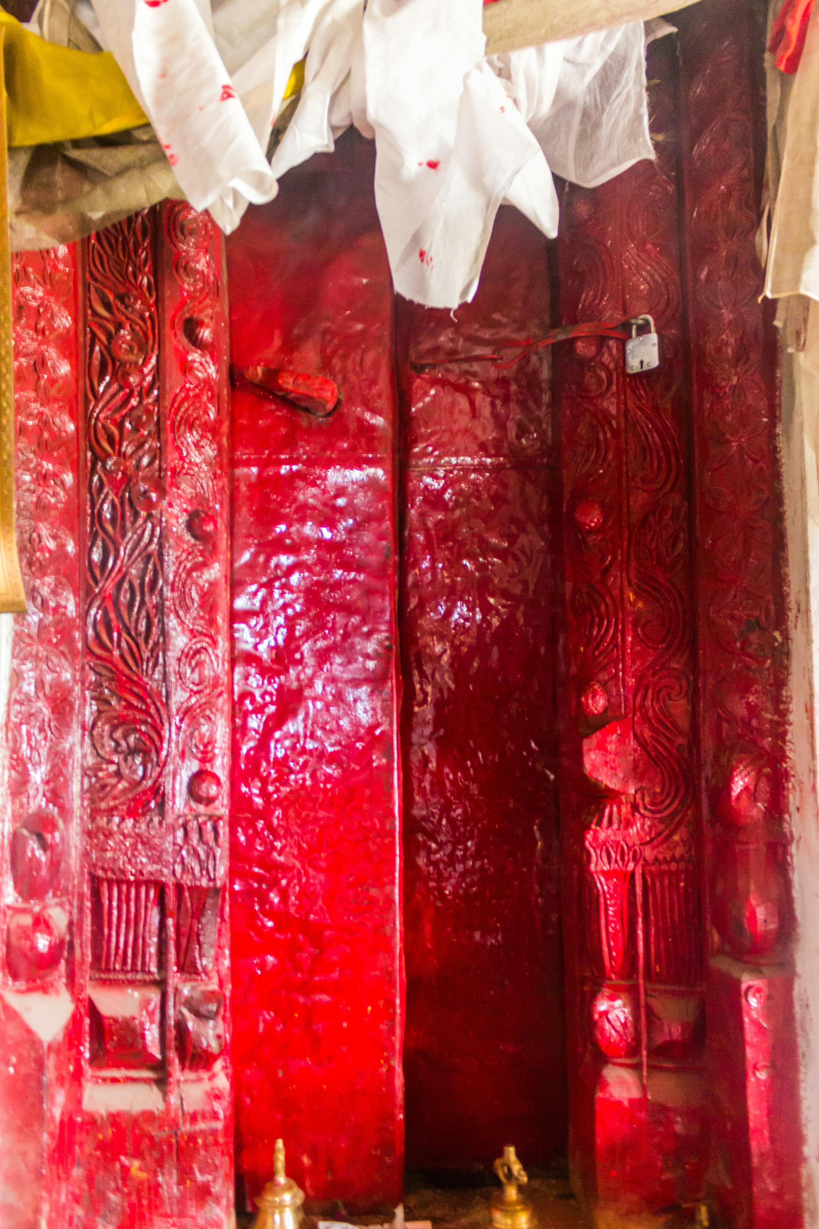 Crimson Corridor: A Narrow Shrine Doorway Framed by Carved Pillars