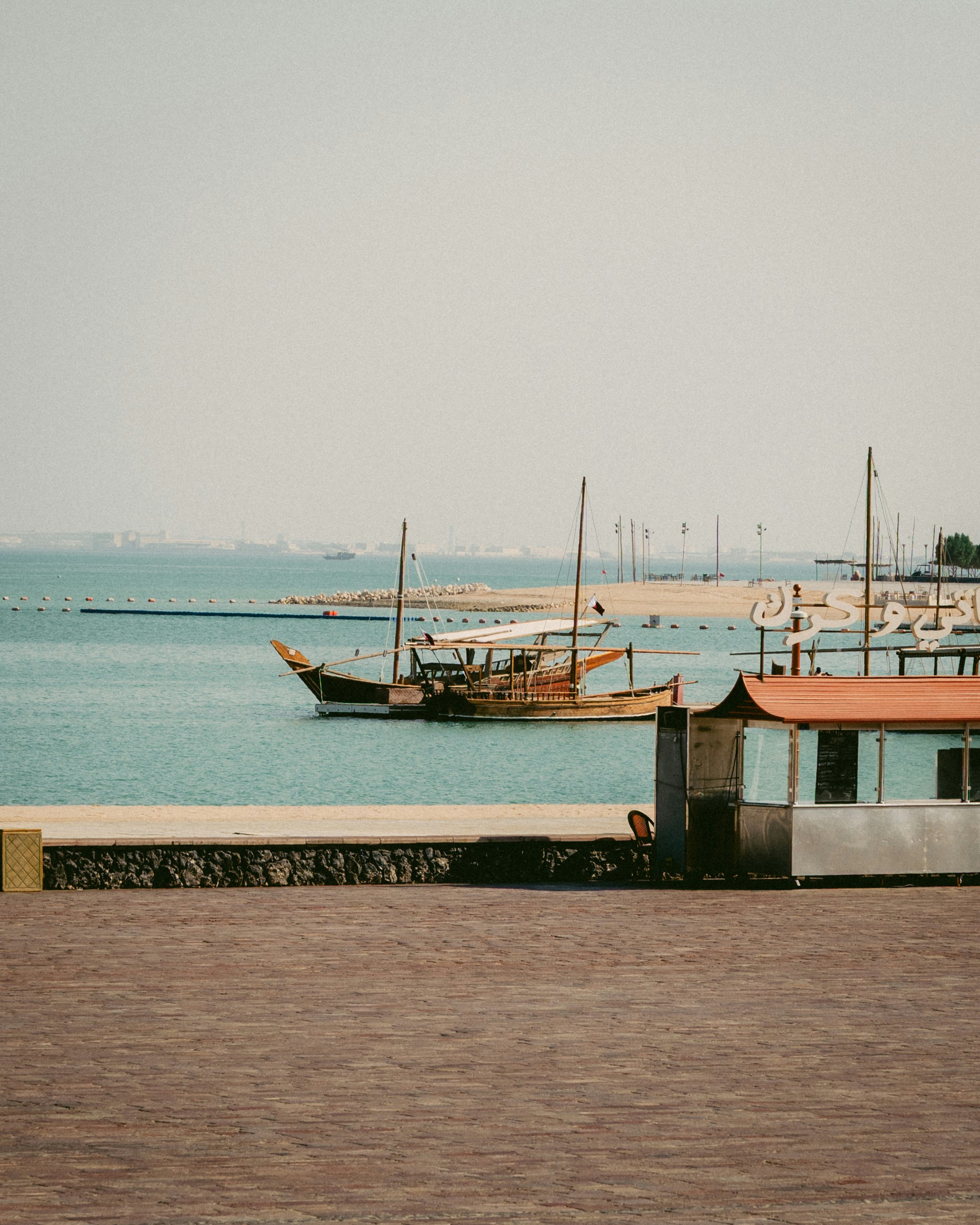 Harbor in Soft Light: Wooden Boats Rest by a Brick Promenade