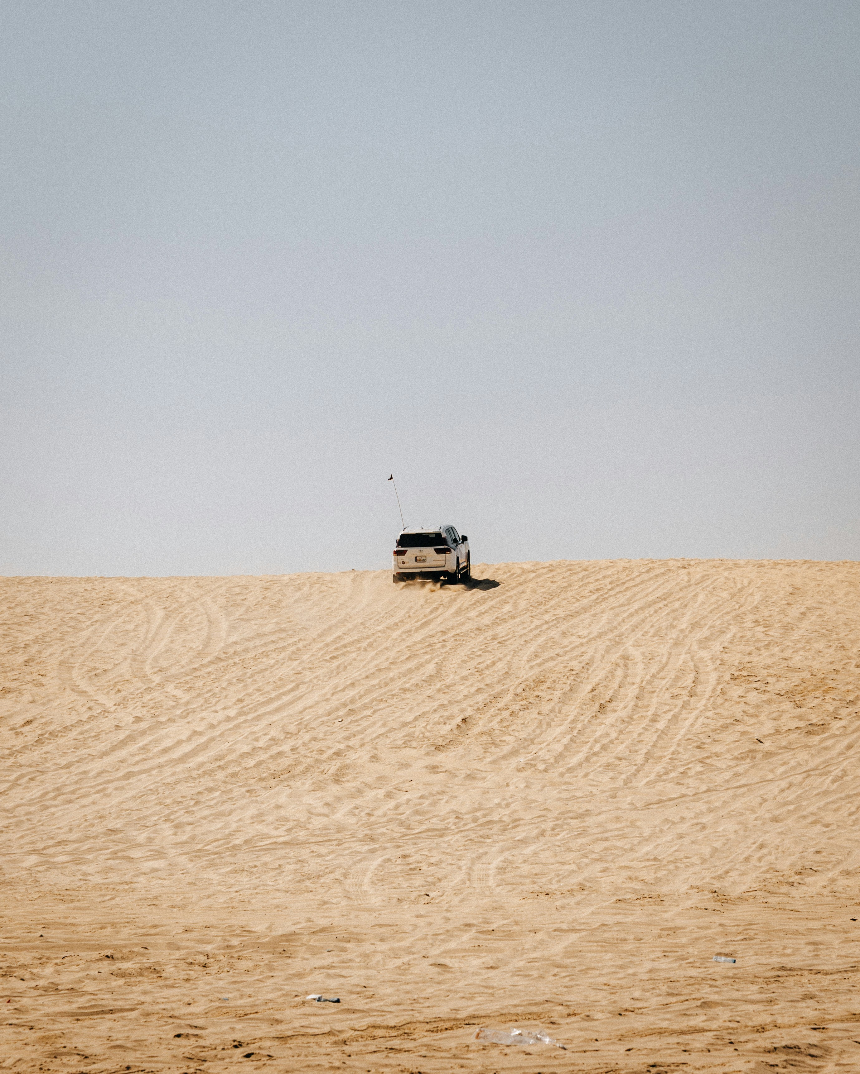 A lone SUV conquers rising dunes