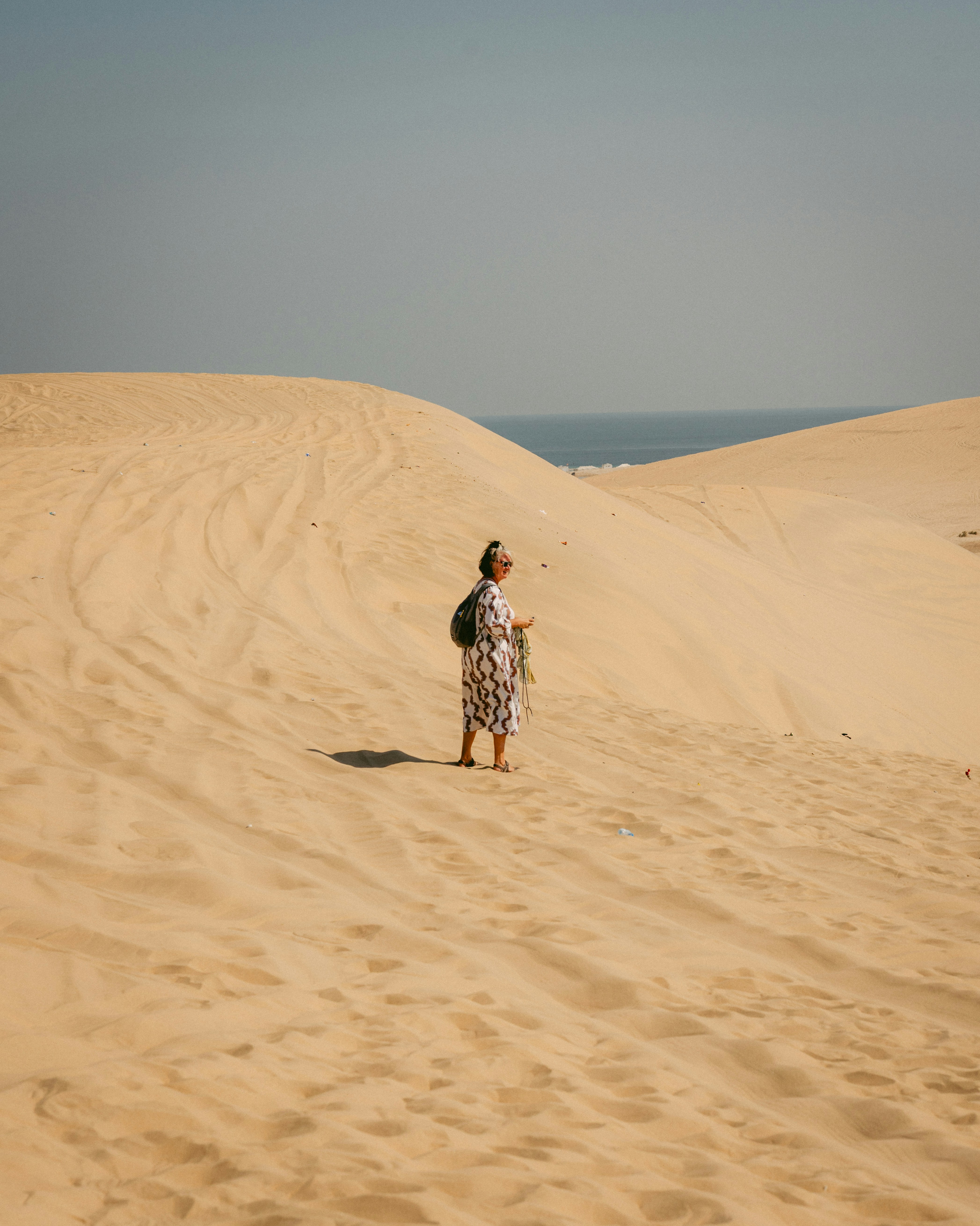 A quiet figure pausing on dunes