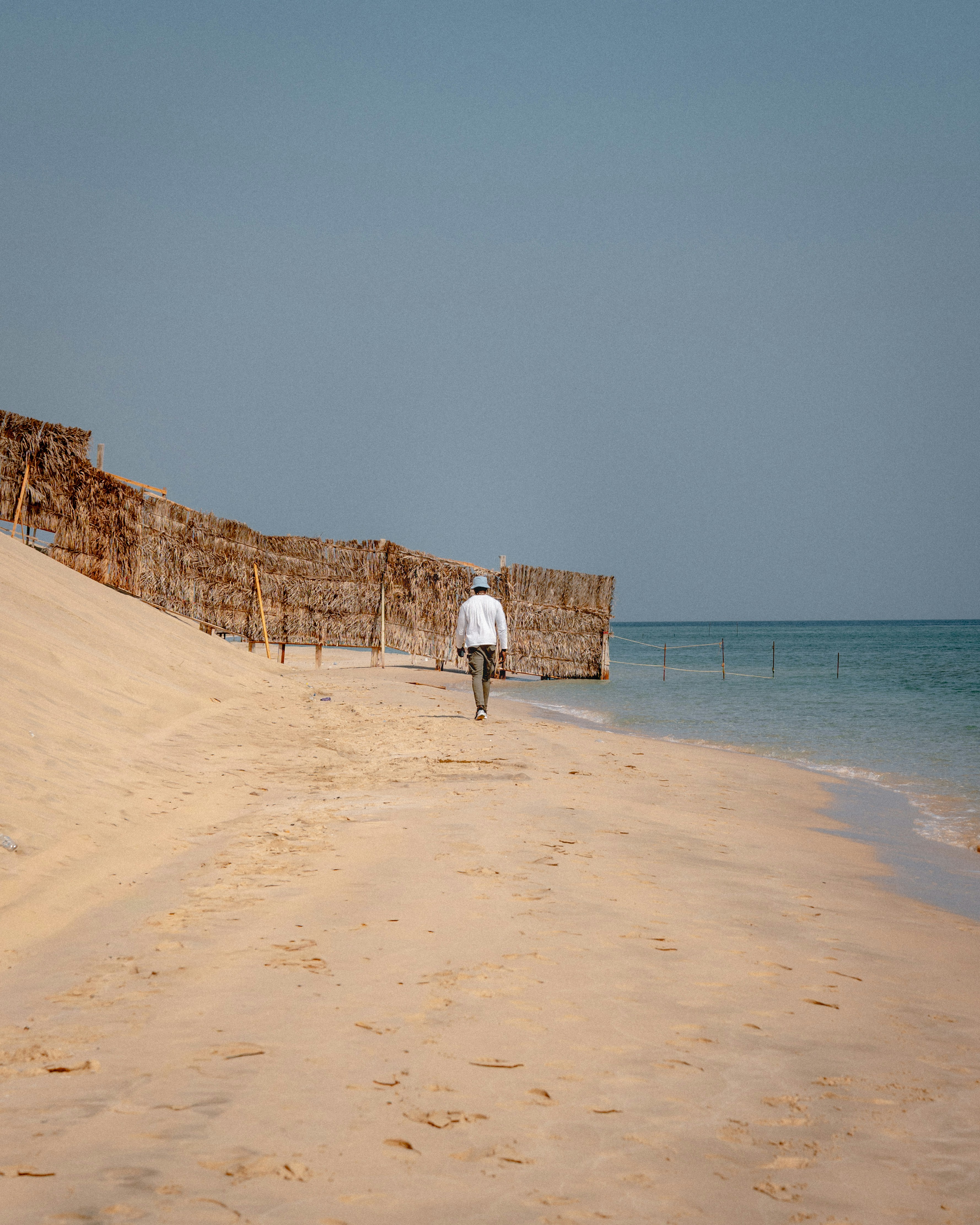 A lone figure walking warm shores