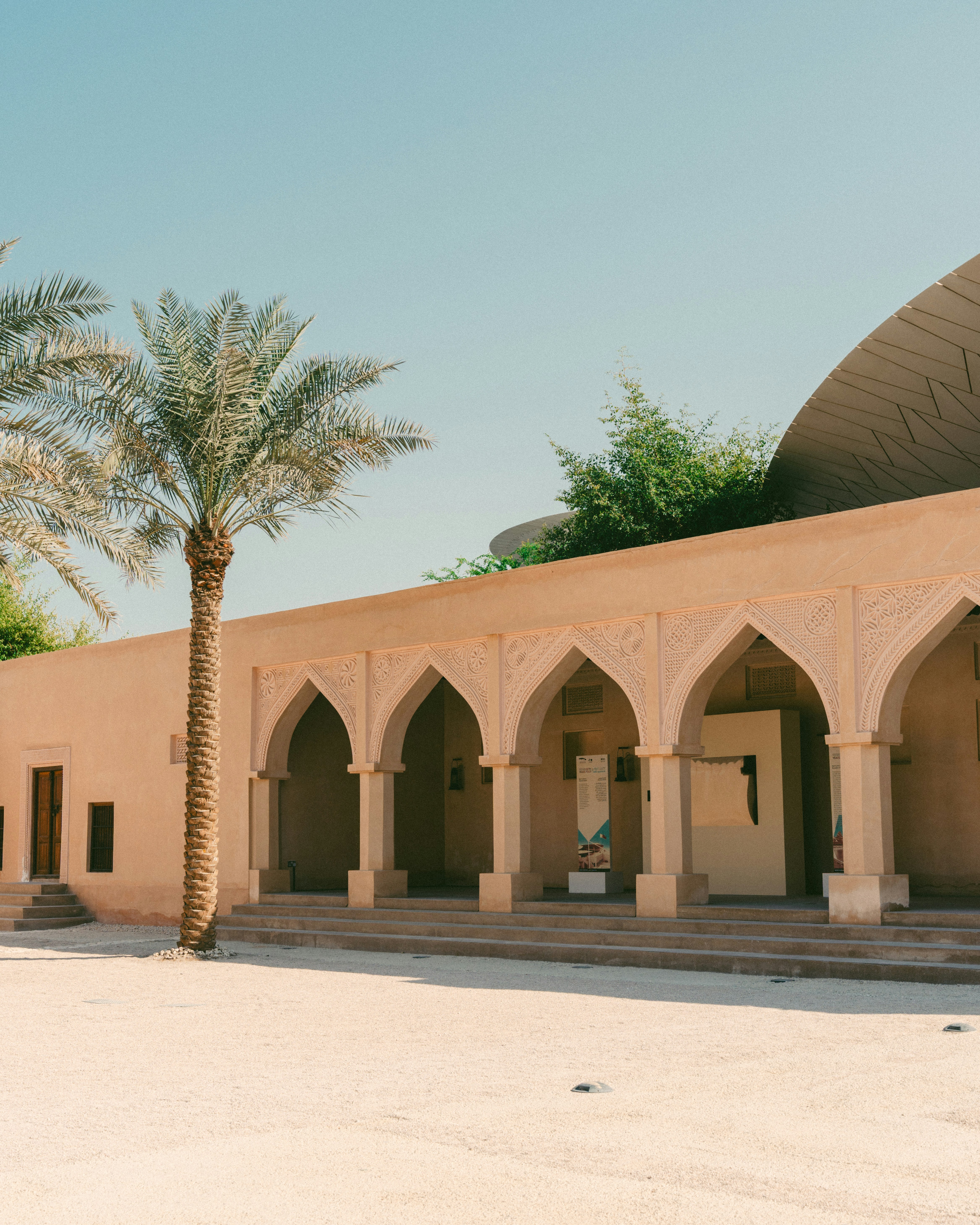 Palm Shadow and Arcaded Facade in a Desert Courtyard