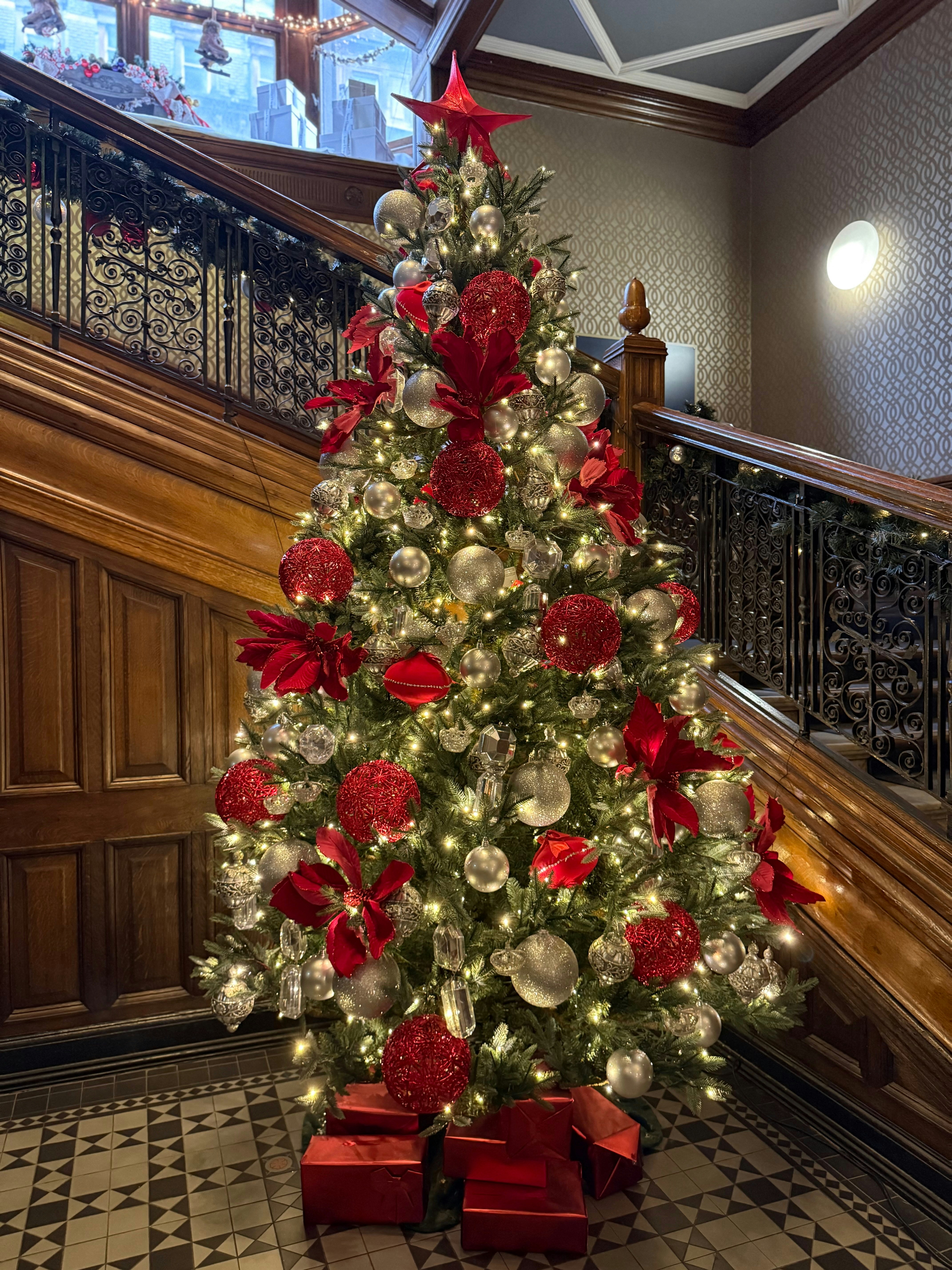 A beautifully decorated christmas tree with red and silver ornaments.