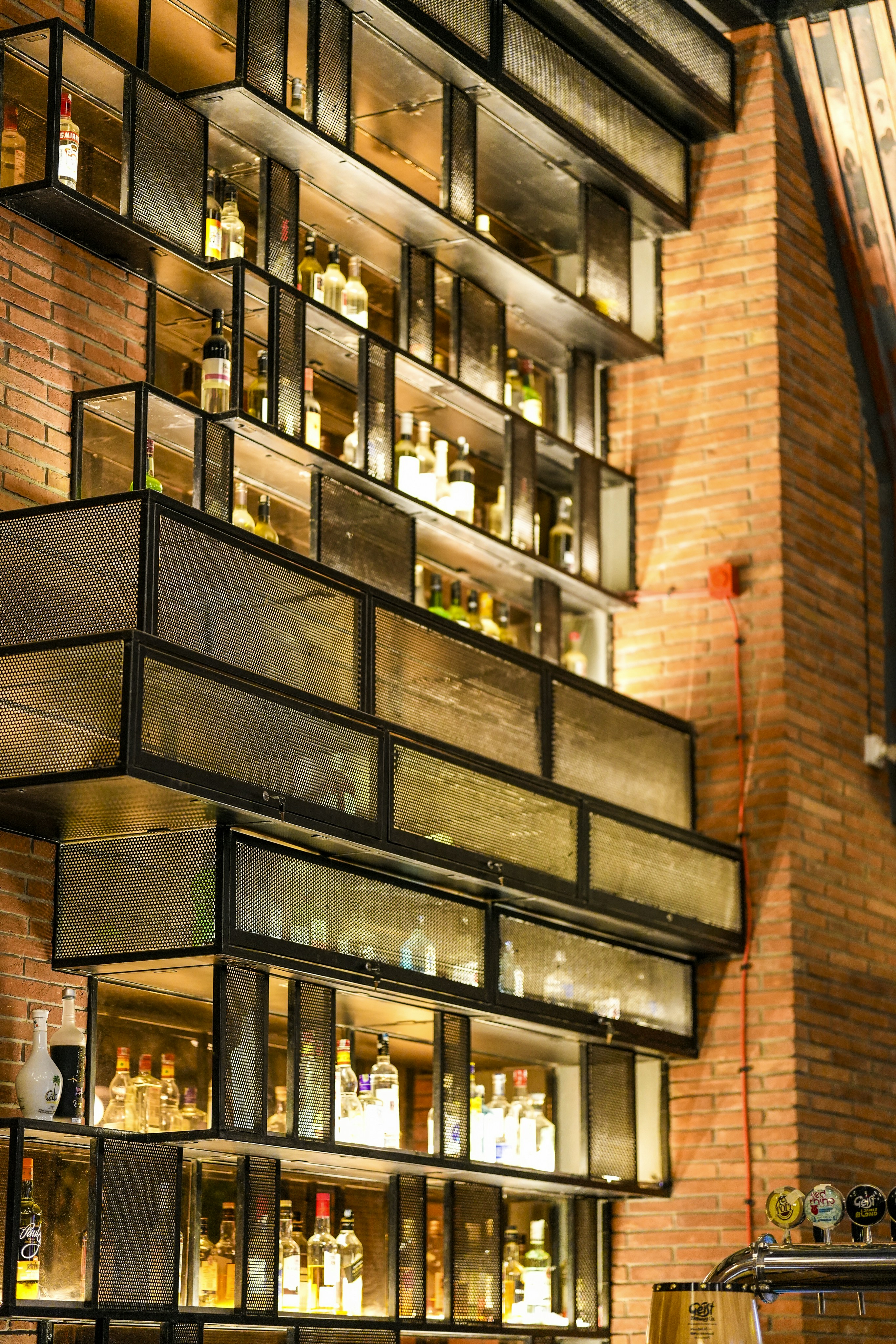 Amber Alchemy Along a Grid of Glass: Bottles on a Brick-and-Steel Bar Wall