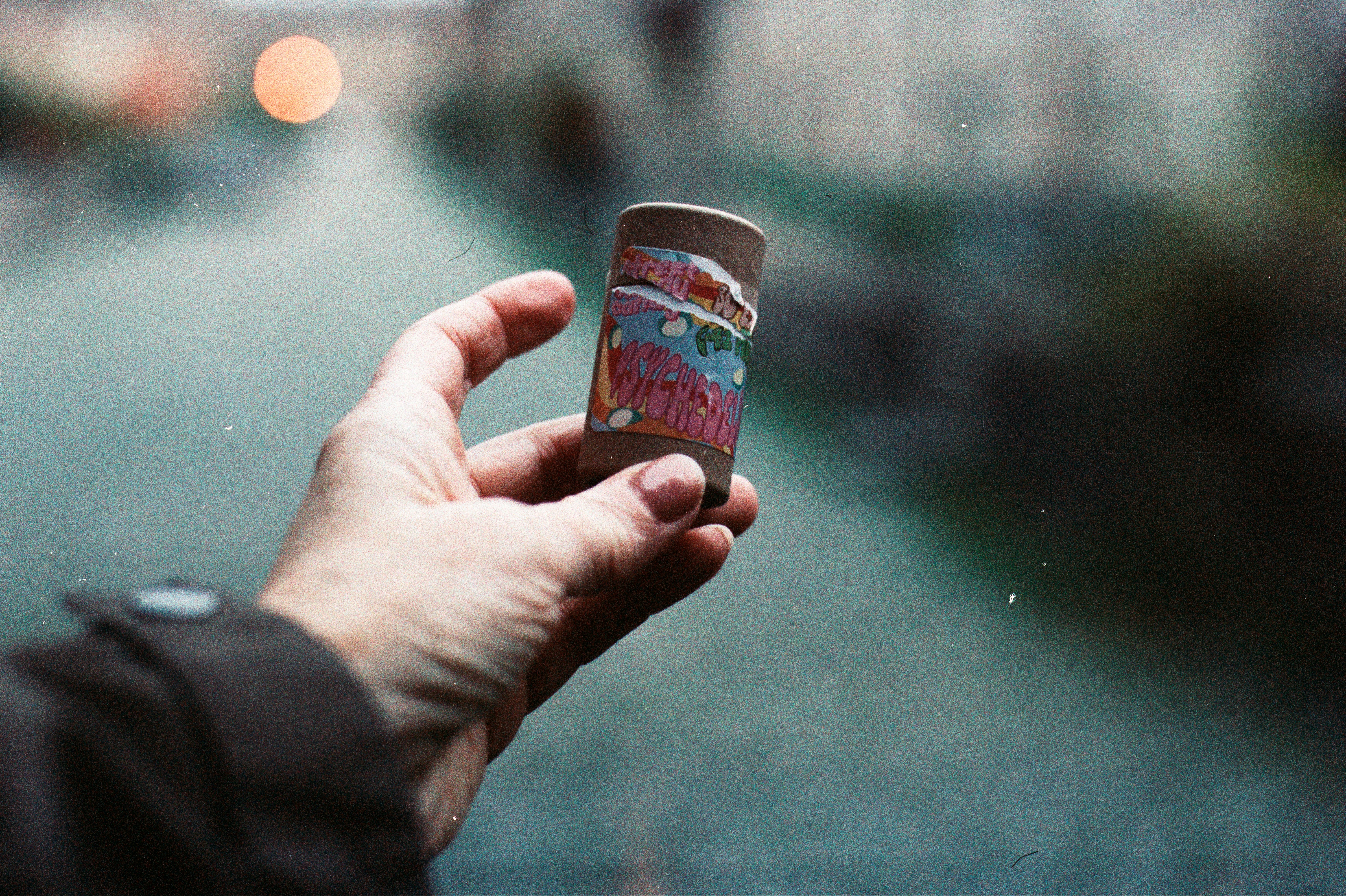 Hand holding small colorful graffiti-covered object
