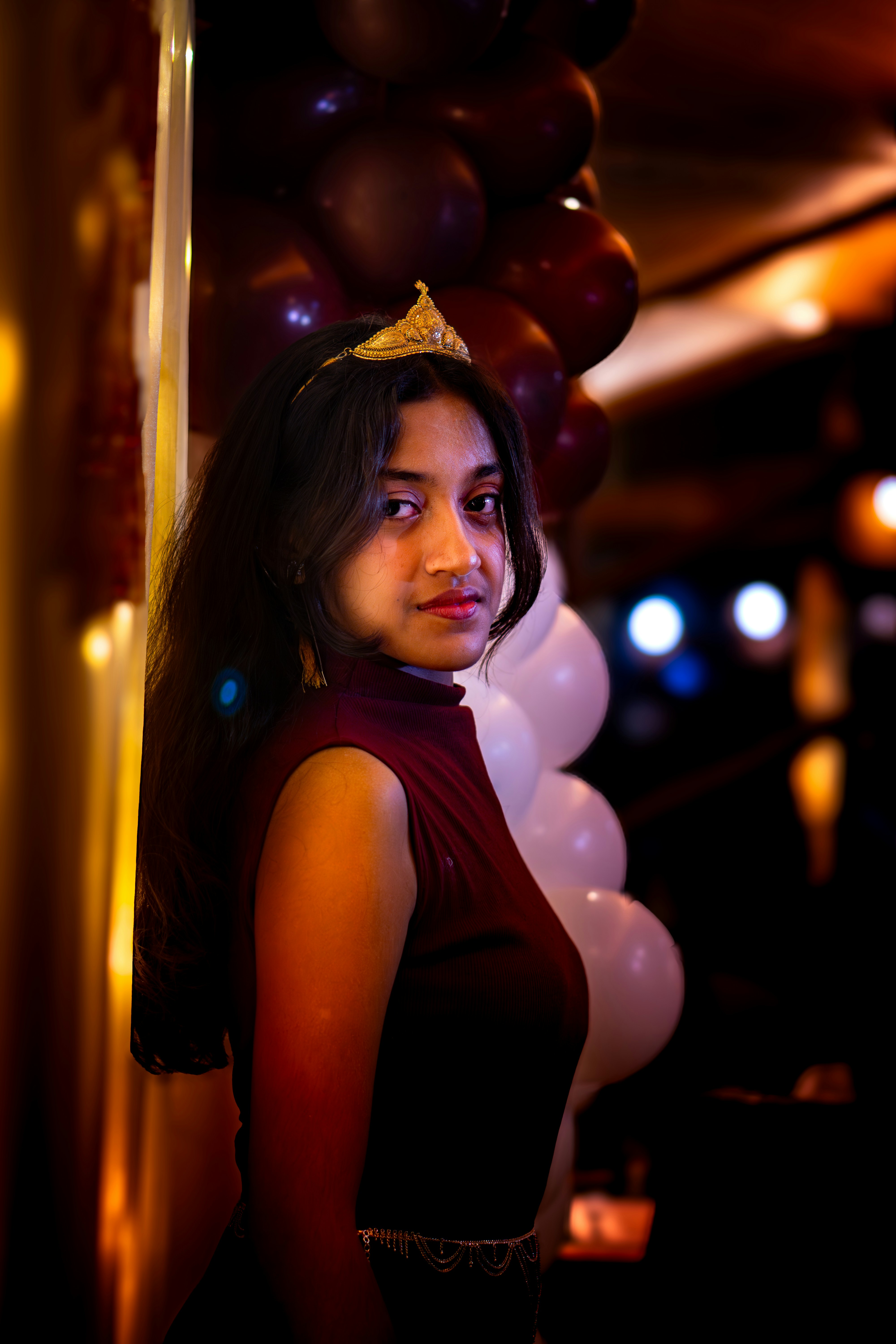 Crowned Glow: A Quiet Portrait Amid Birthday Balloons