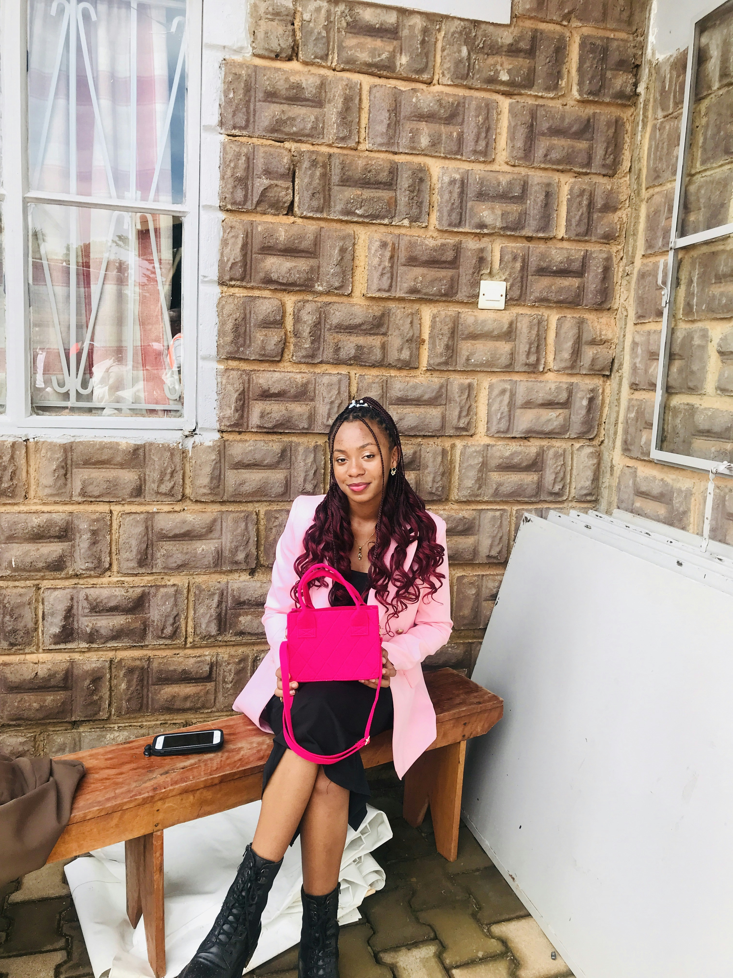 Pink-coated poise: a stylish moment on brick and bench