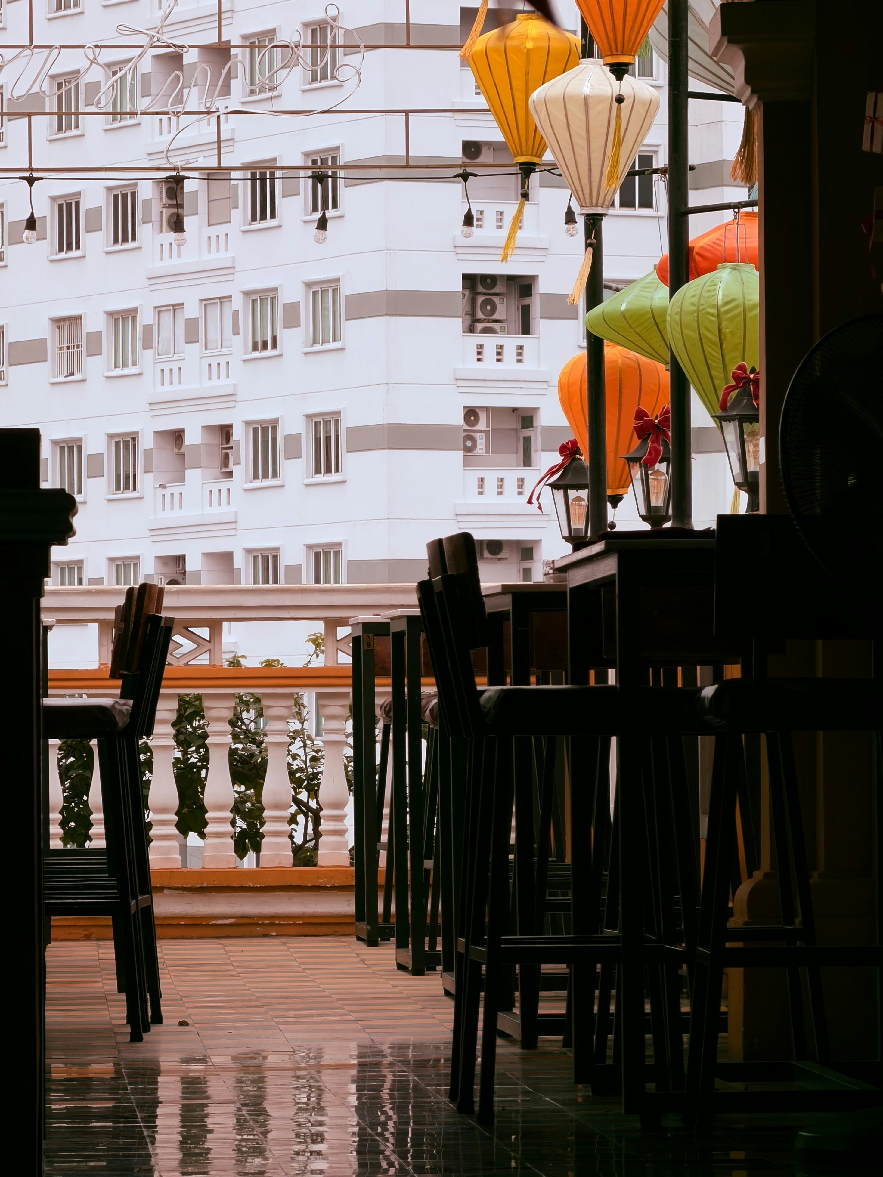 Colorful Lanterns Framing a Rooftop Café Against a White Cityscape