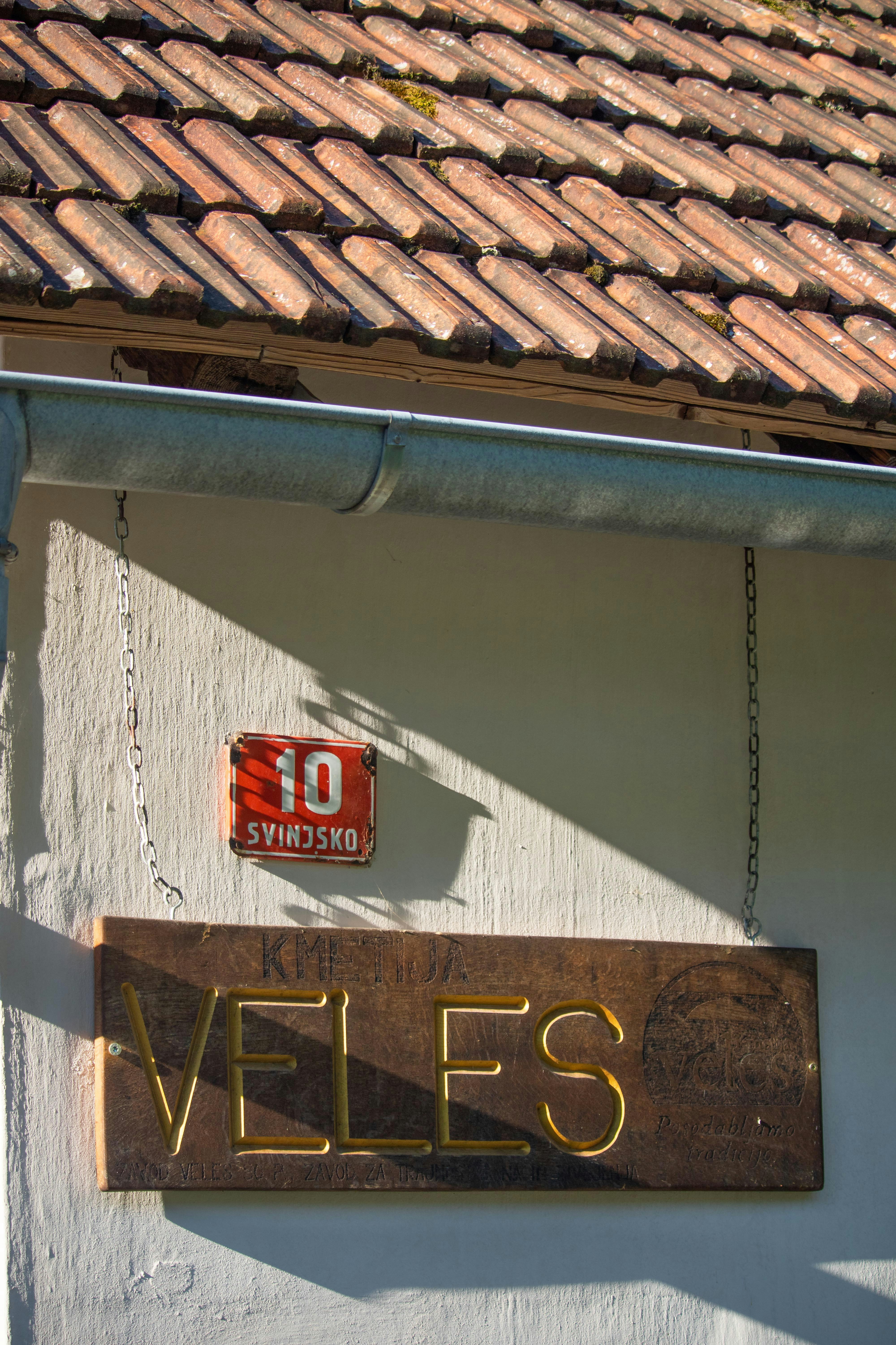 Weathered Veles Sign Under a Sunlit Clay Tile Roof