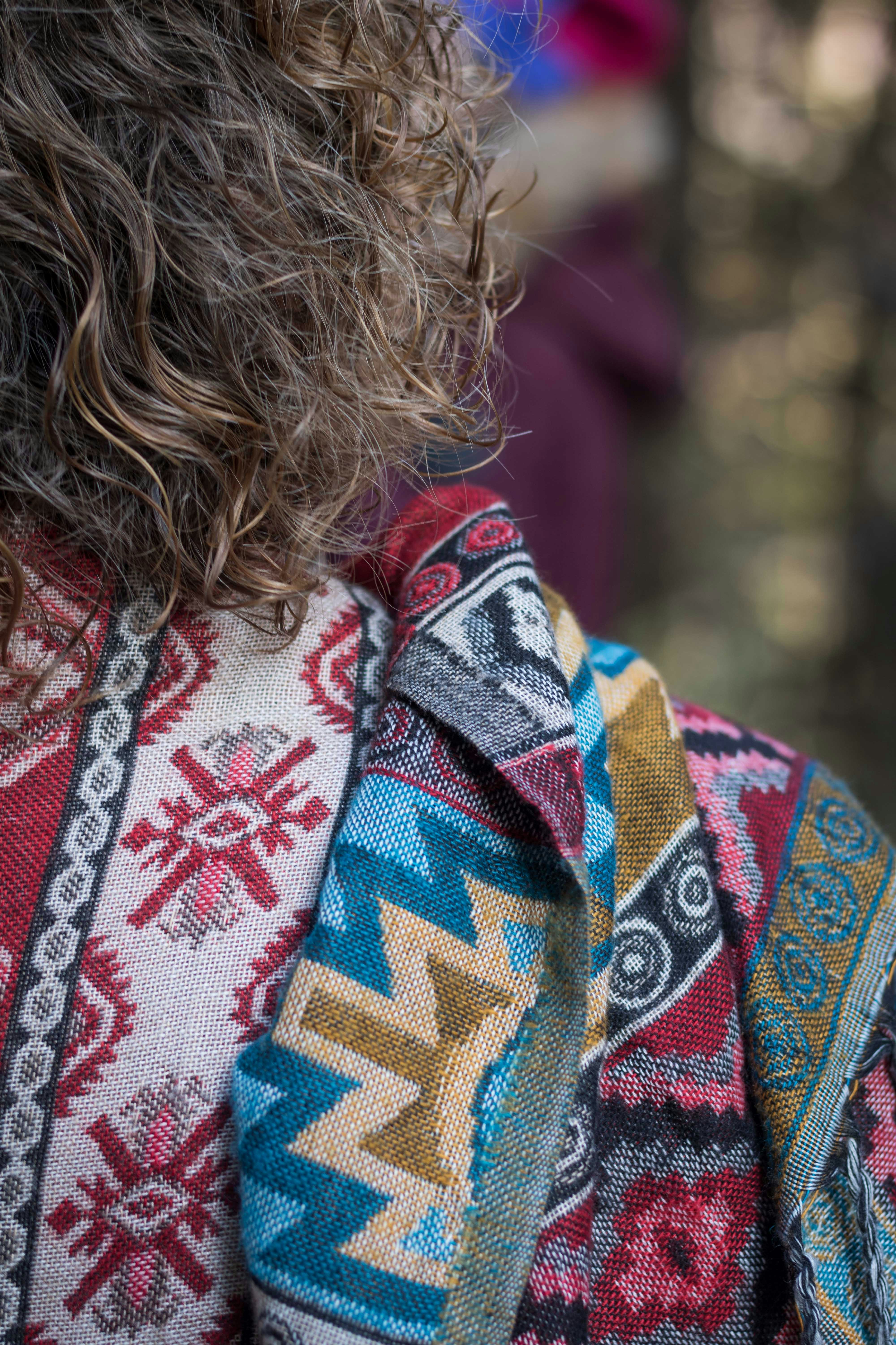 Kaleidoscope of Fabric: Close-Up of Curly Hair Framed by a Multicolored Geometric Scarf