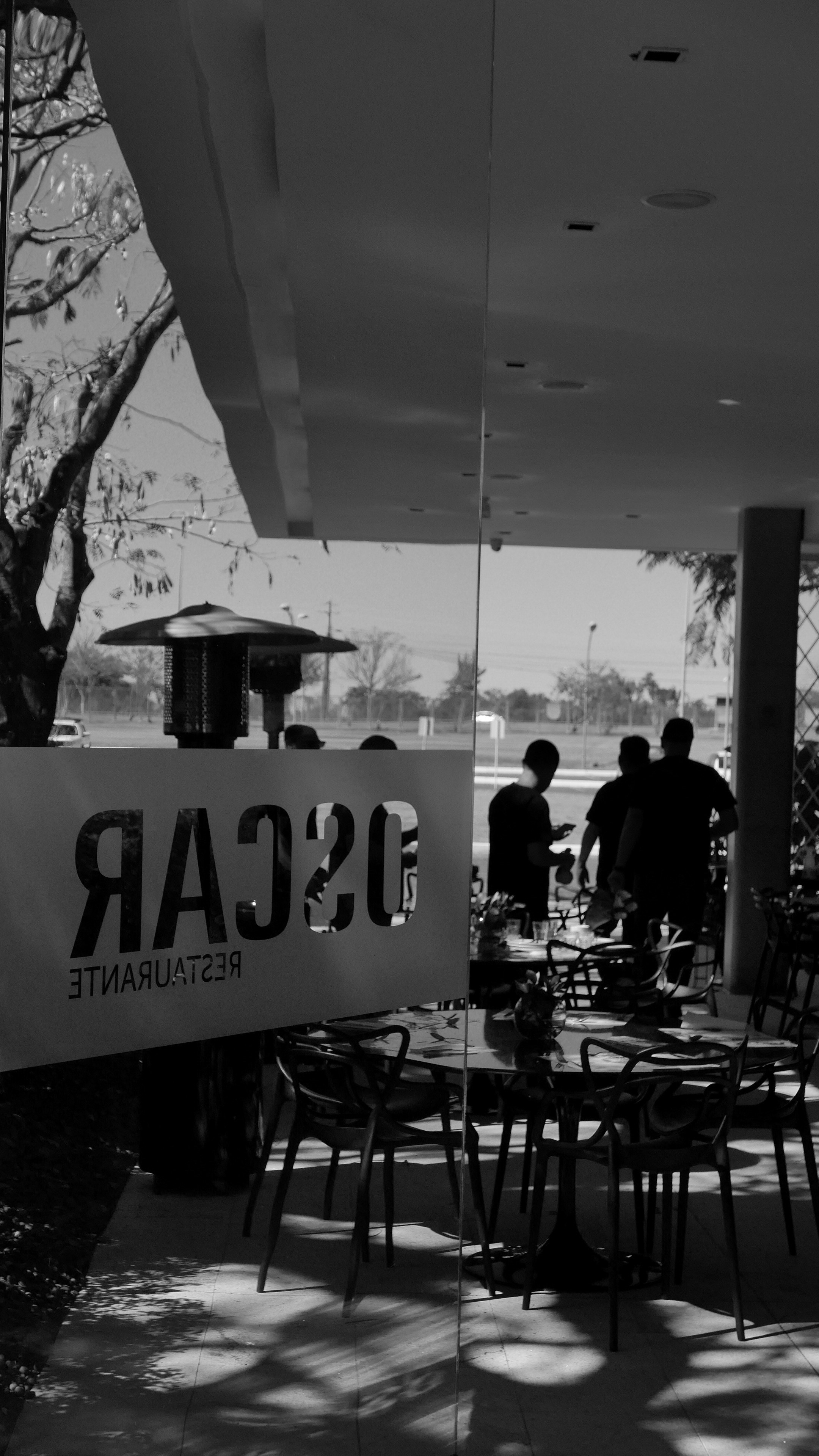 Silhouetted Patrons Gather Under a Glass-Front Café Canopy