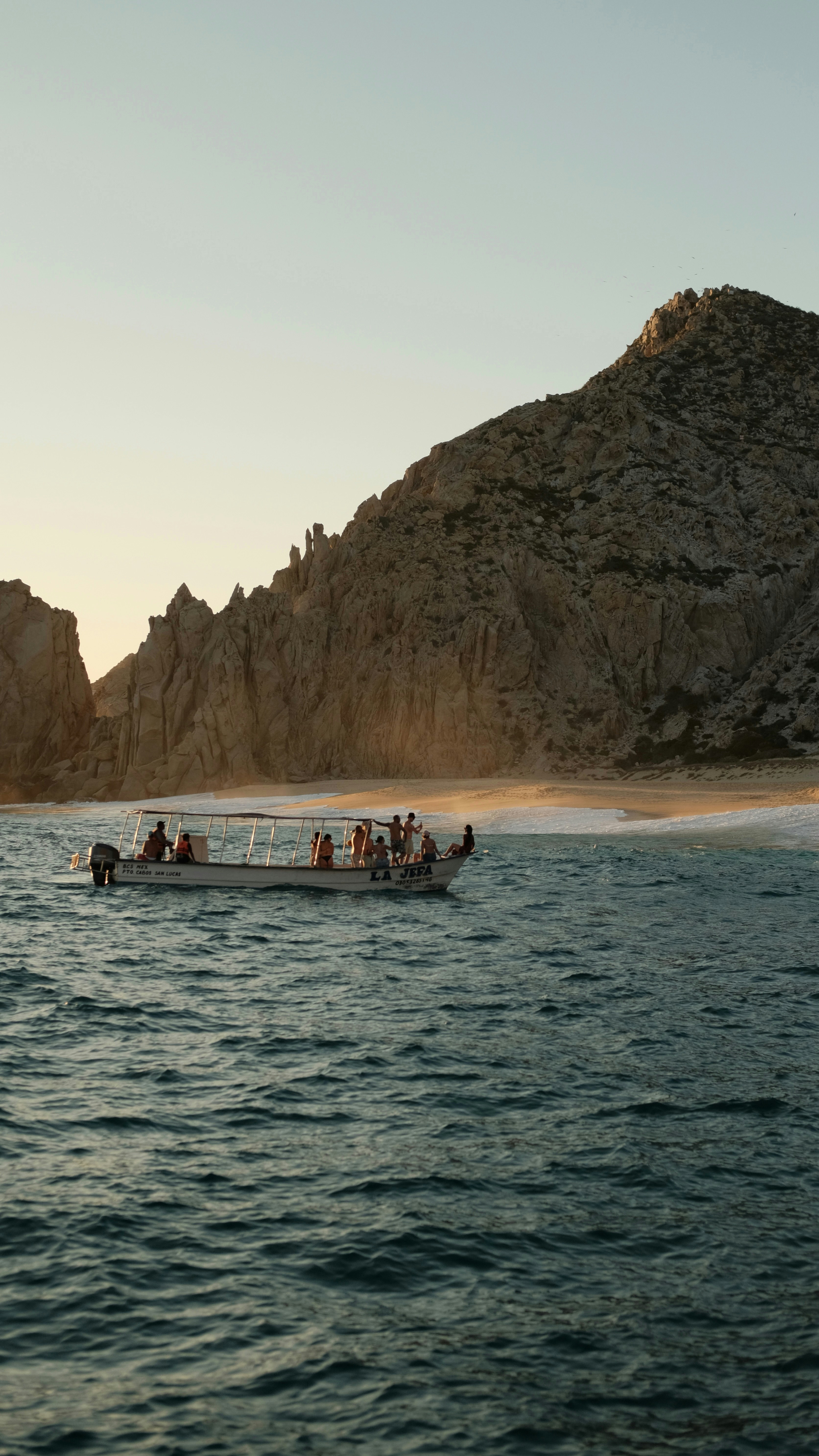 Dusk Tour Boat Hovering Near Rugged Coastal Cliffs