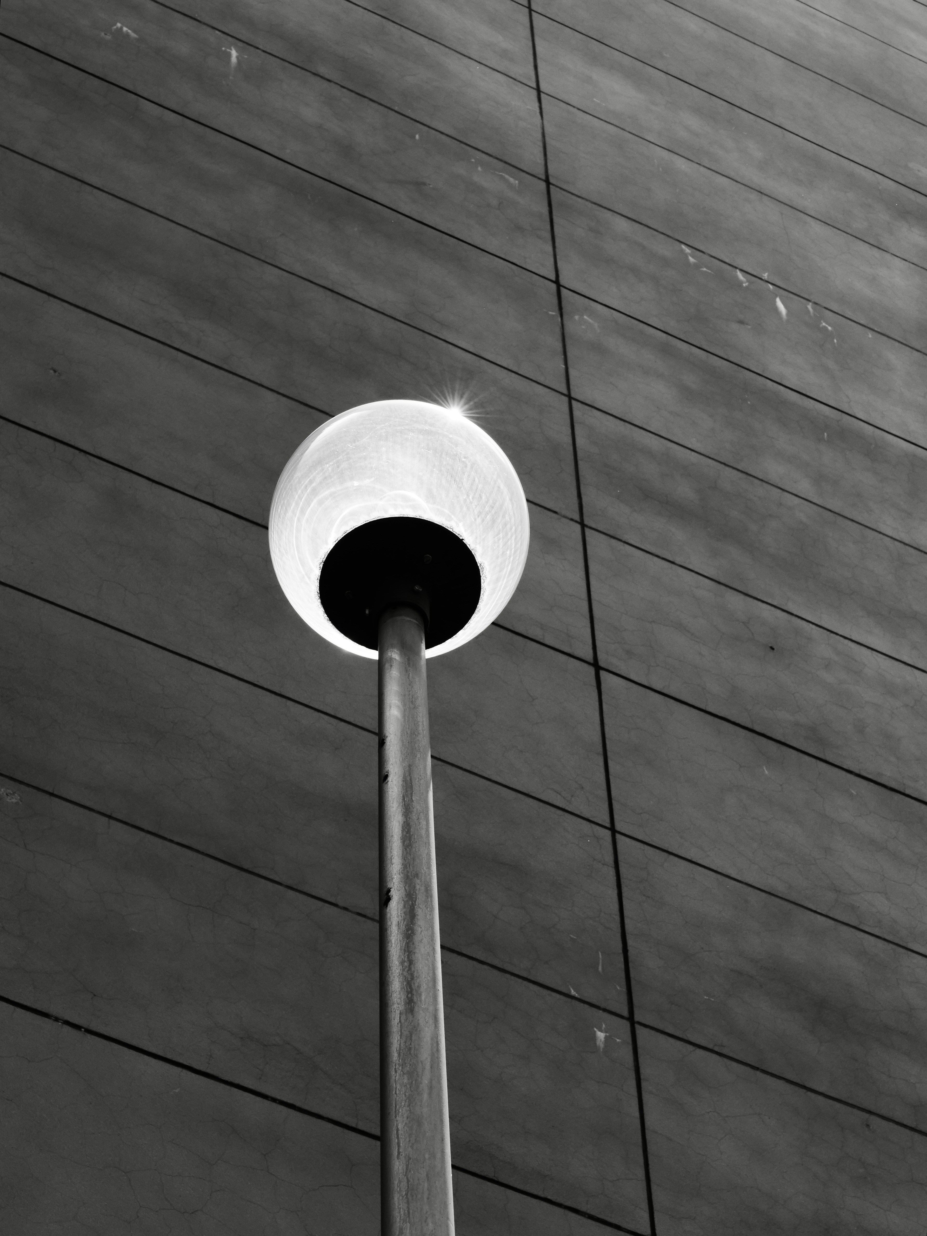 Lumen at the Grid: a streetlamp silhouette against a tiled facade