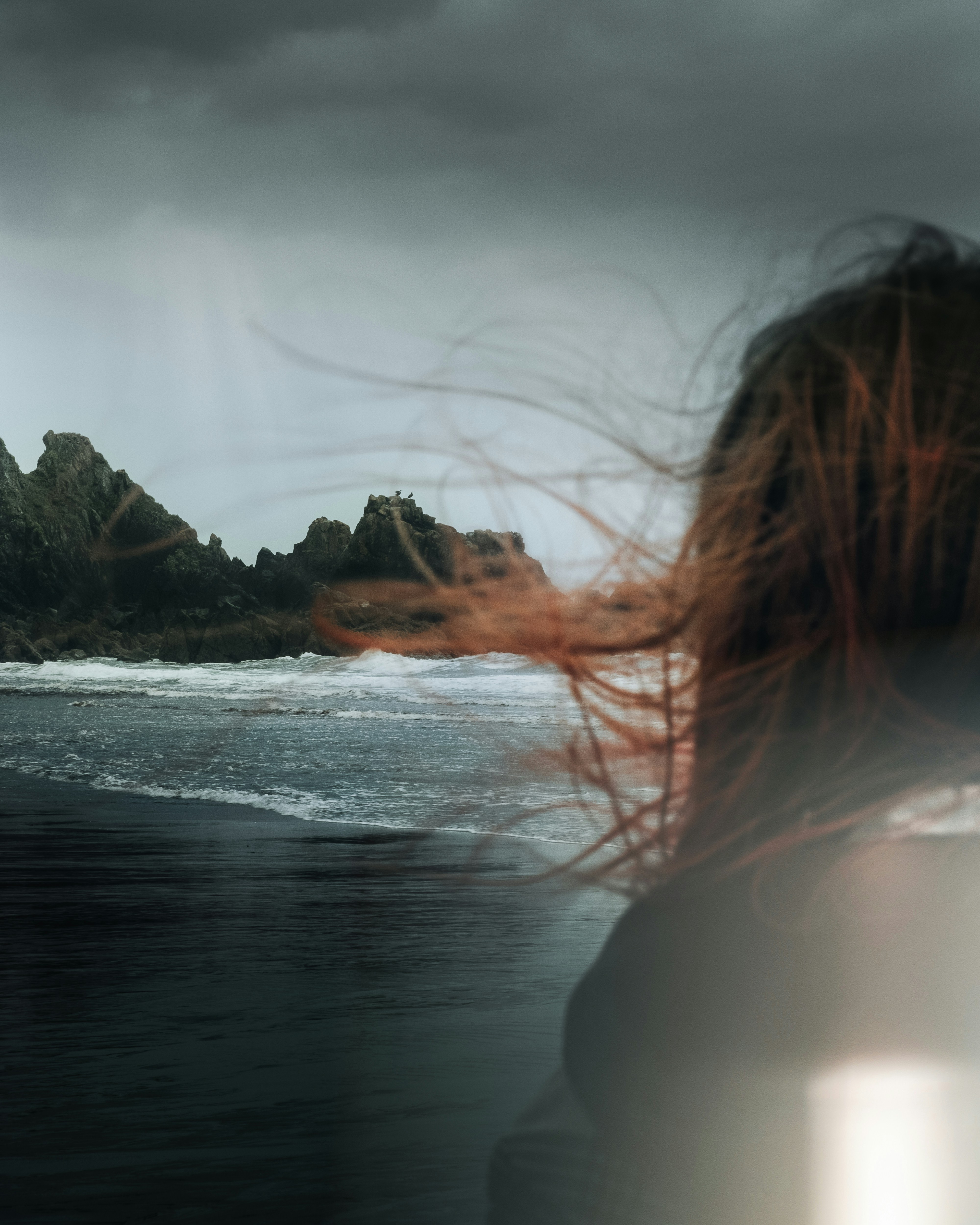 Wind-Tossed Horizon: Jagged Rocks and a Red-Haired Foreground