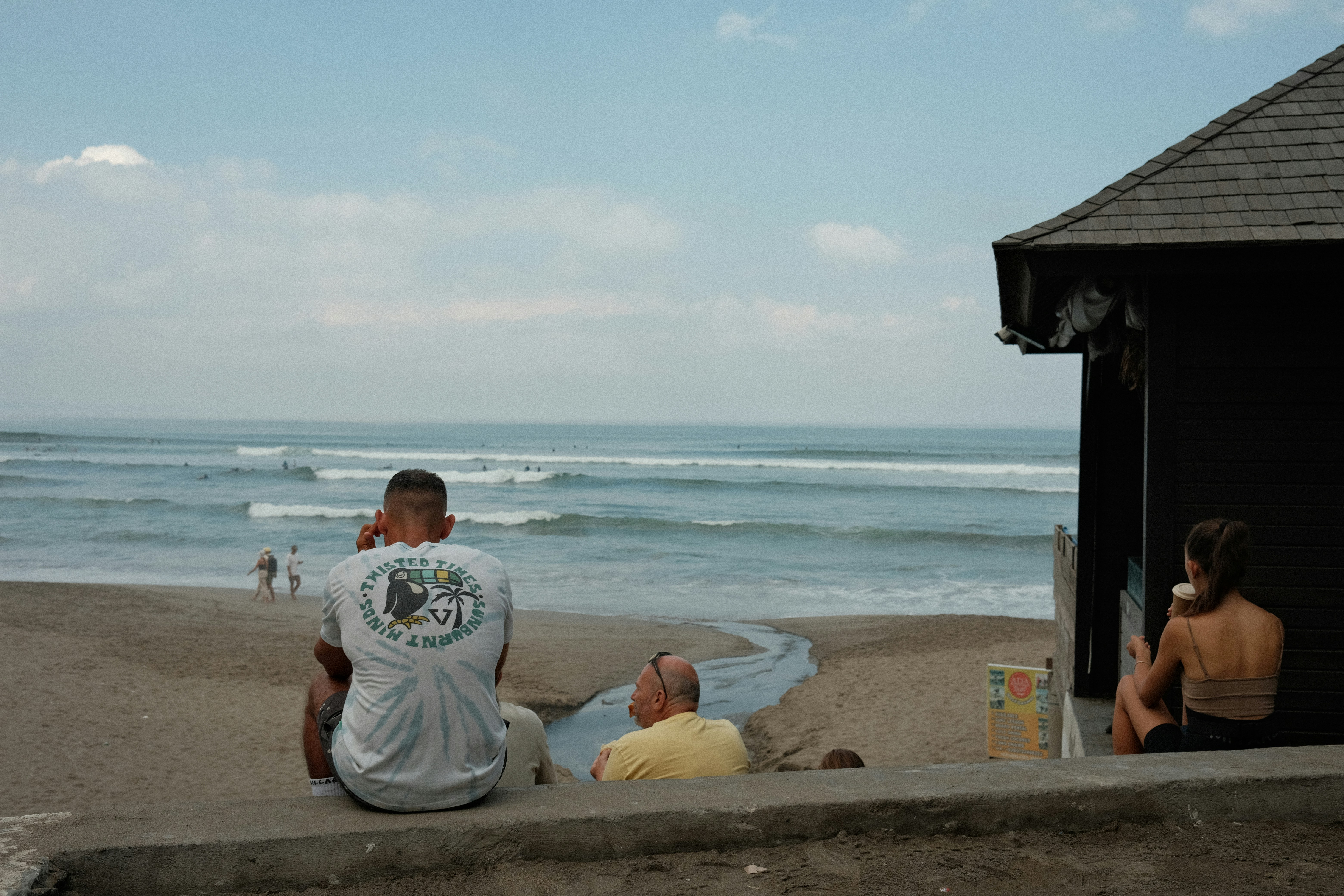 Coastline Assembly: a quiet gathering on the seawall beside a weathered shack