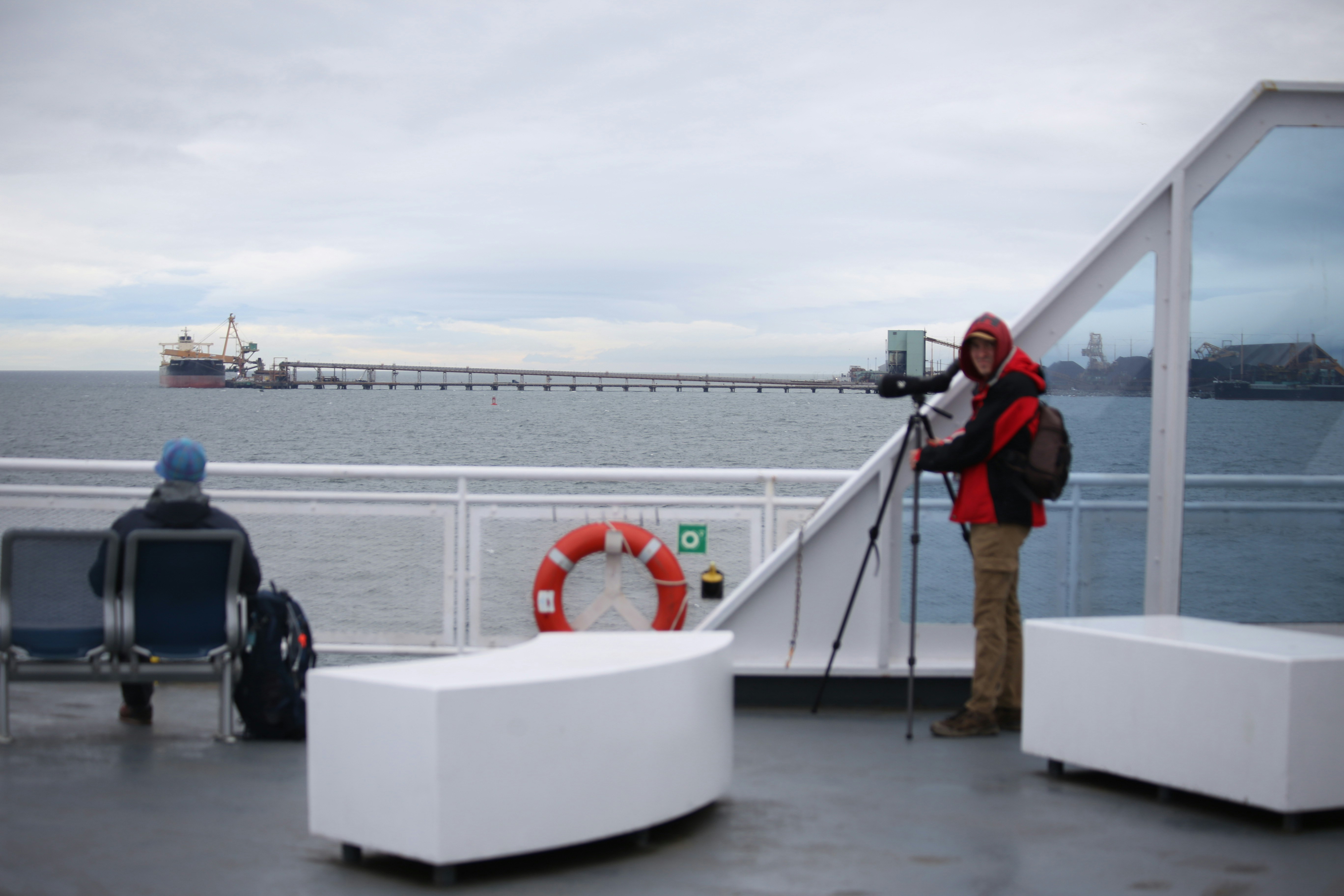 Pierside Gaze: The Red-Jacket Photographer Lines Up the Horizon