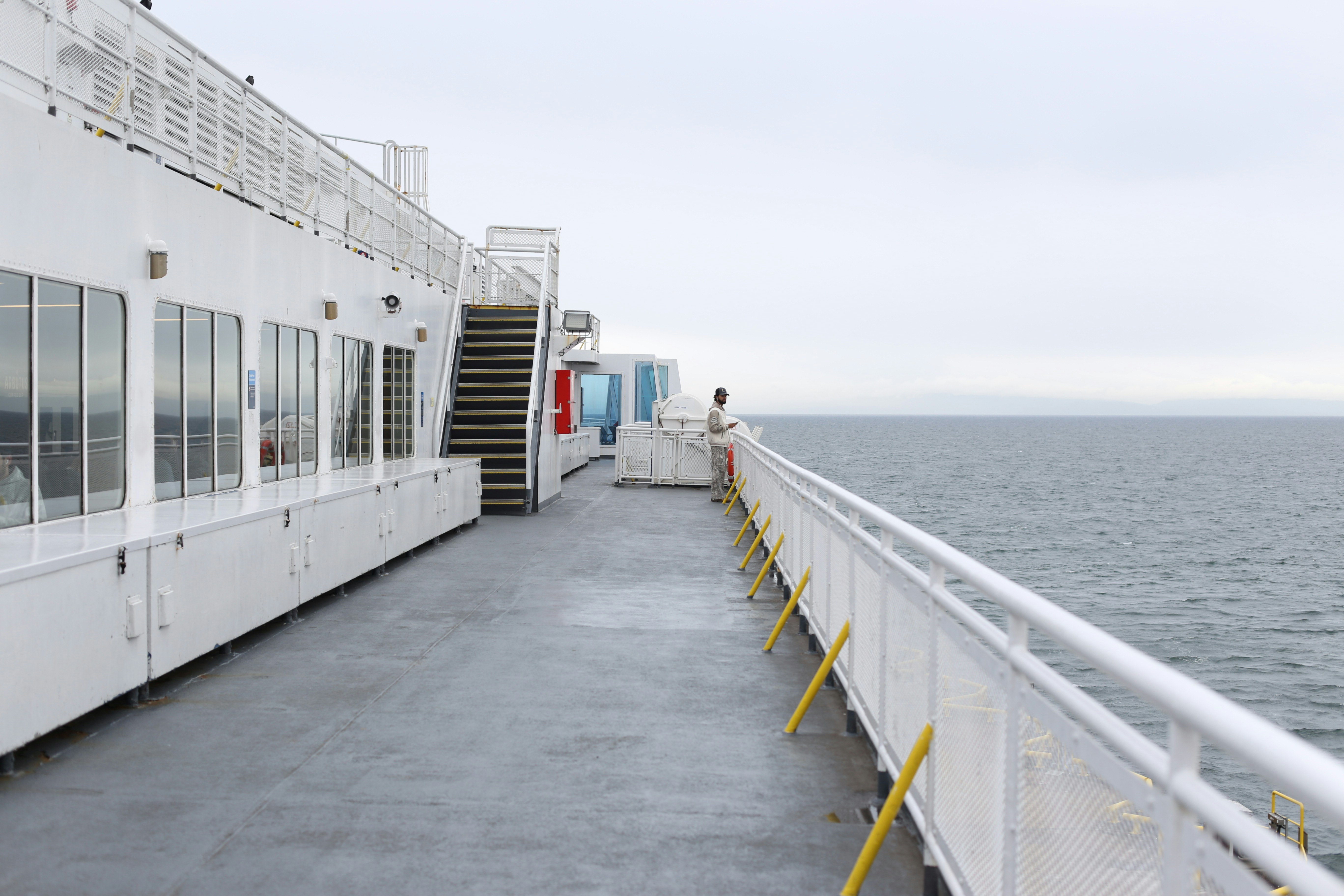 Horizon Walk: A lone figure at the rail of a ferry deck watching the sea