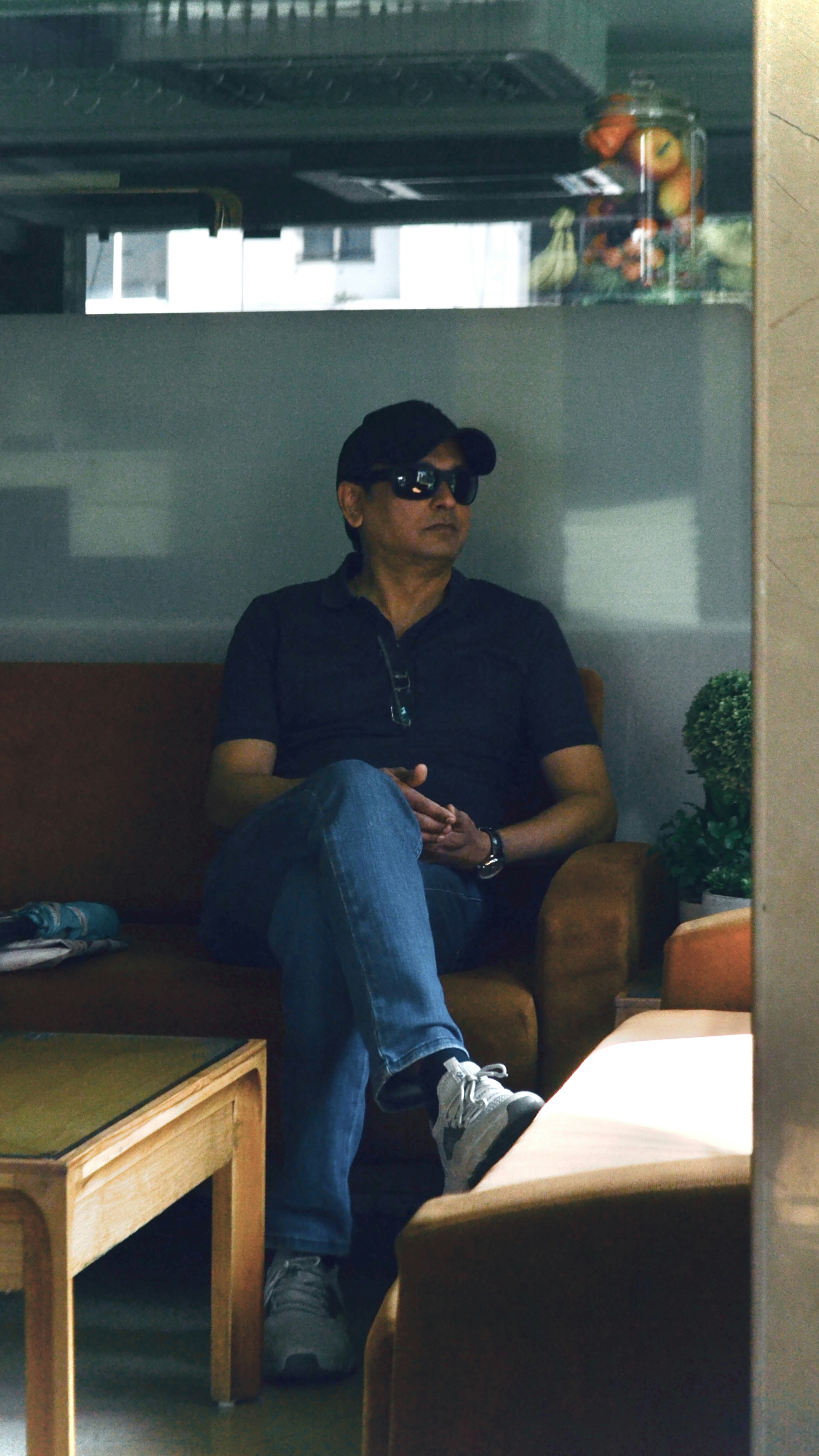 Shadowed Calm: A Sunglasses-Clad Moment in a City Lounge