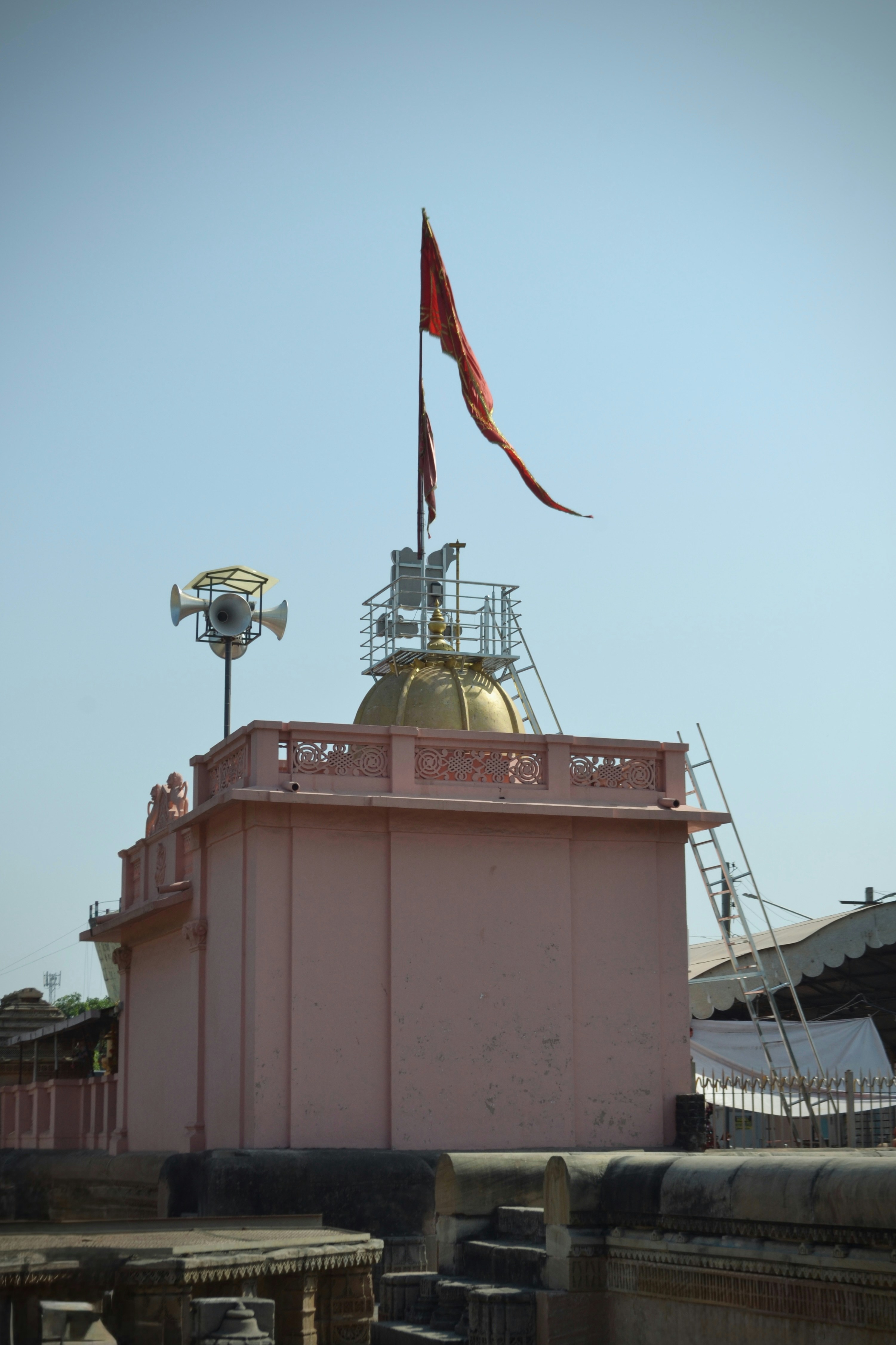 Gold Dome Over a Pink Temple Roof with a Tattered Red Banner