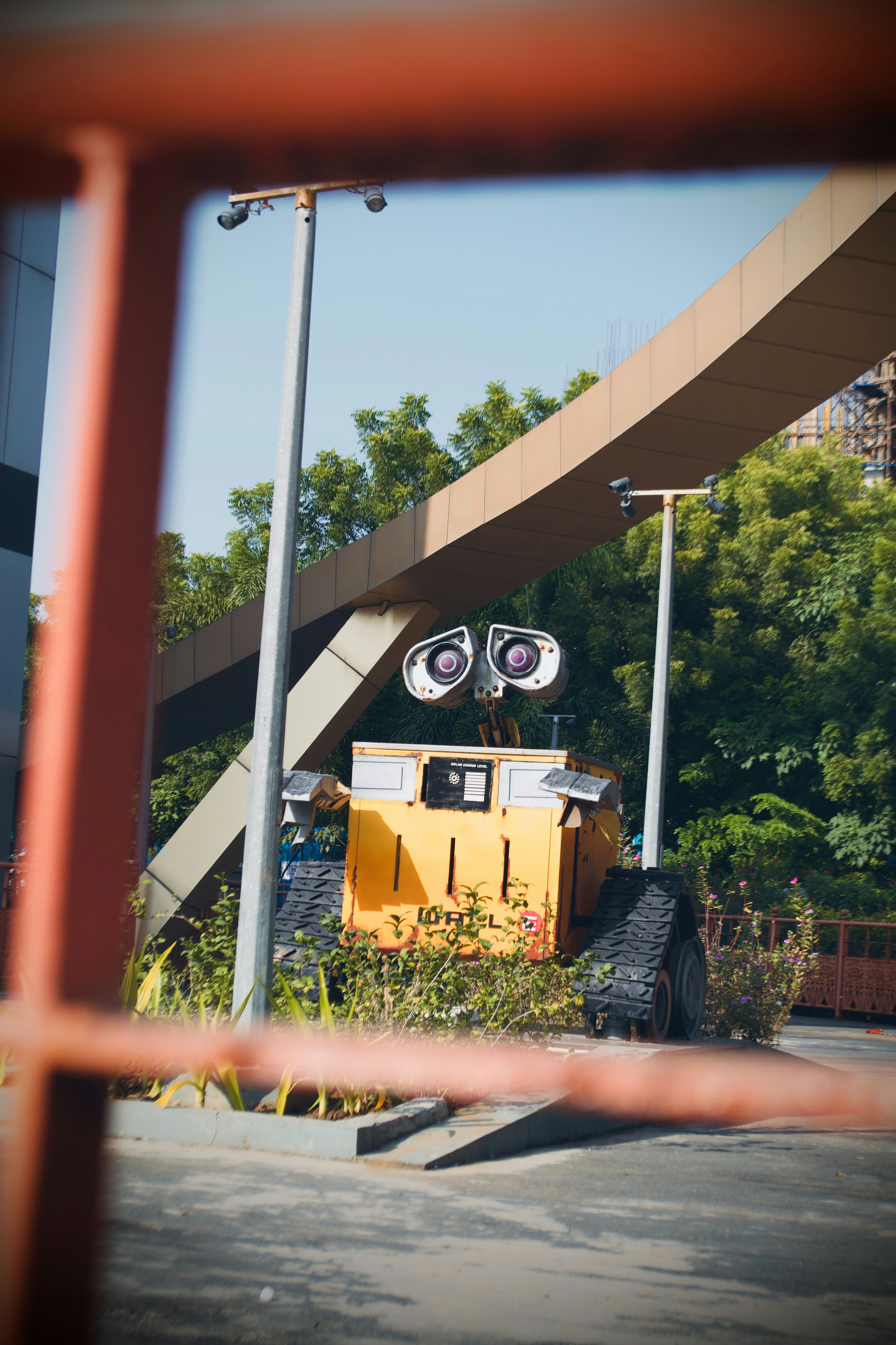 Idle Sentinel: A WALL-E-inspired Loader Framed by Red Rails Under a Pedestrian Bridge