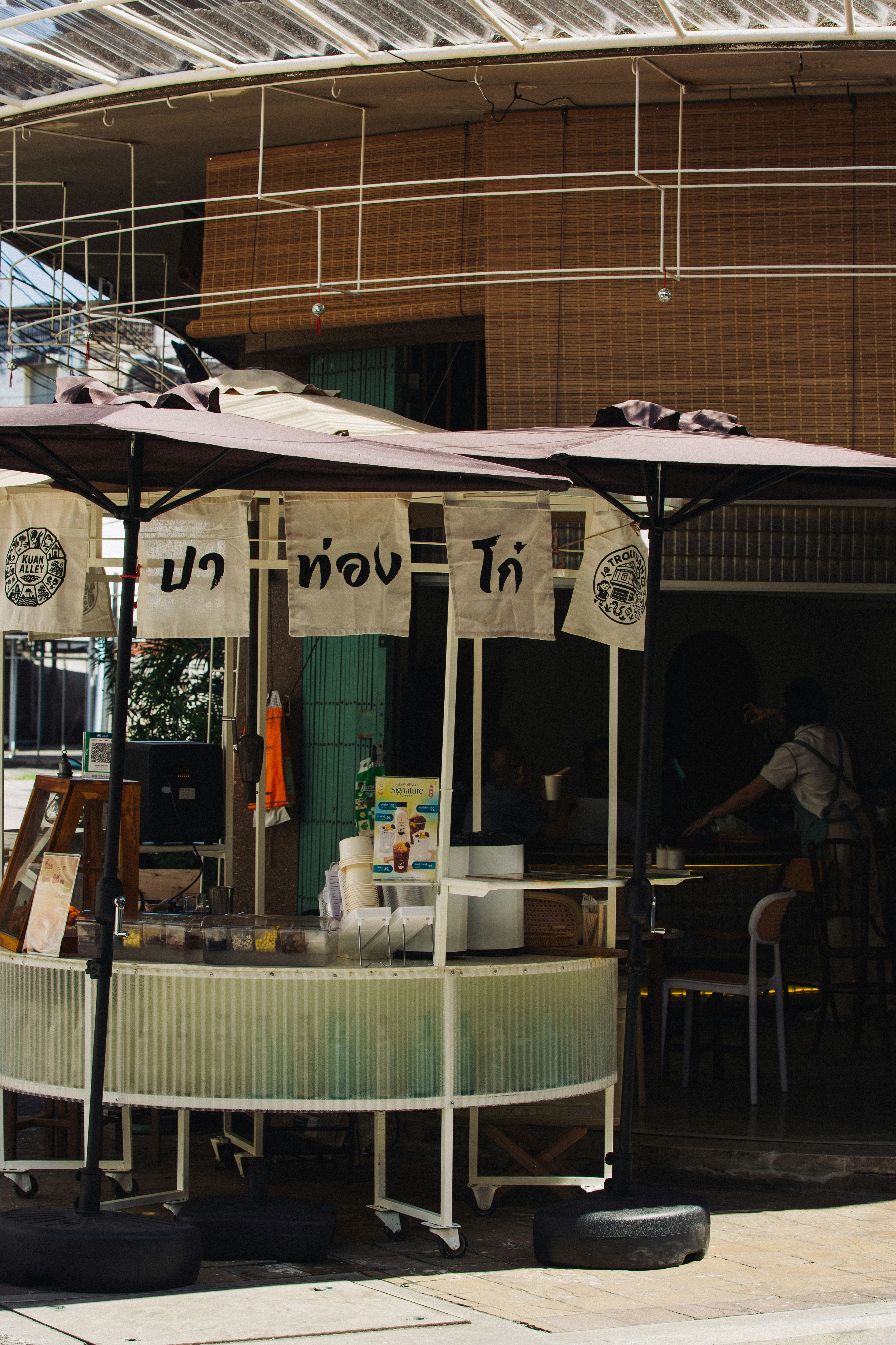 Under the Canopies: a Thai street-food stall beside a brick facade