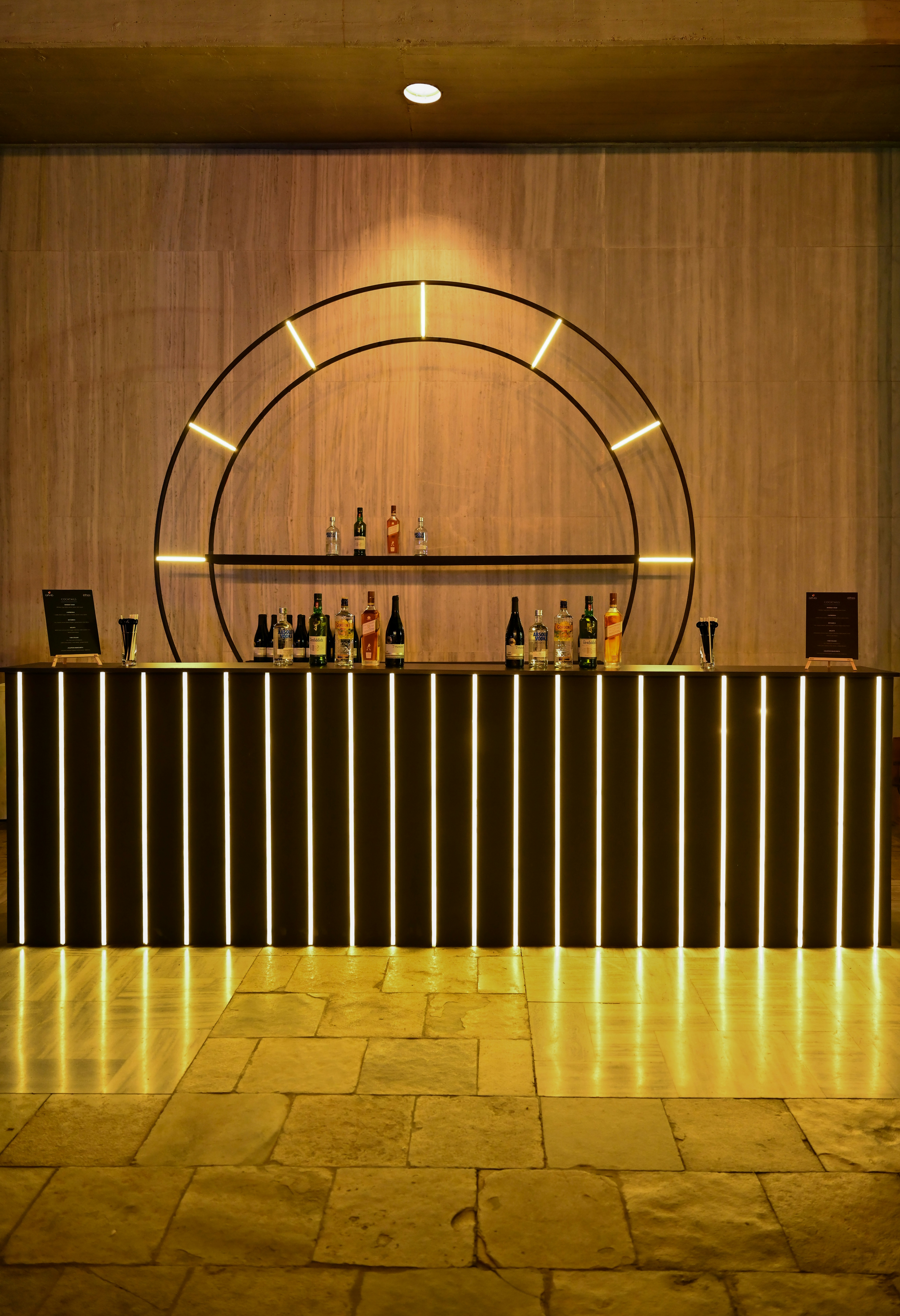 Amber Halo Framing Bottles: A Circular Light Ring Over a Minimal Bar