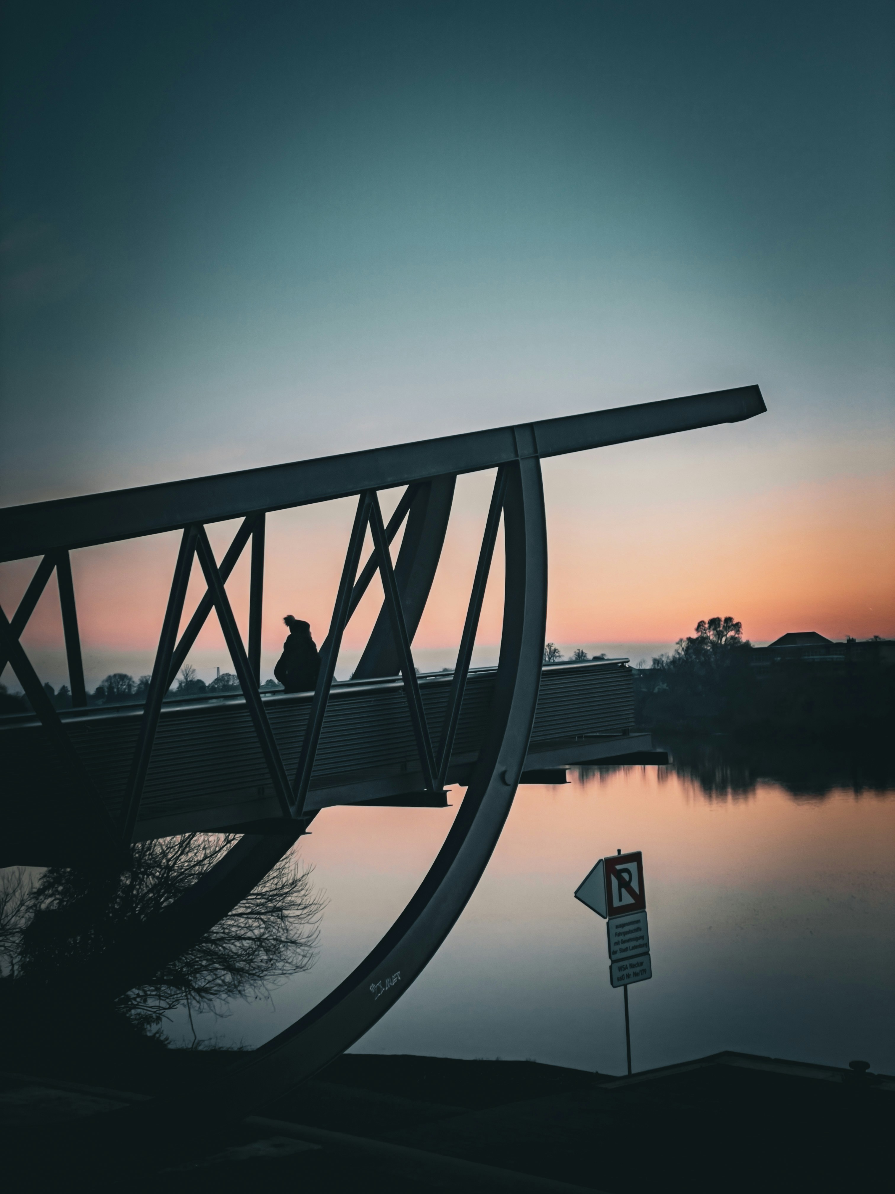 Dusk on the Crescent Bridge: A Lone Silhouette Traverses a Curved Arch