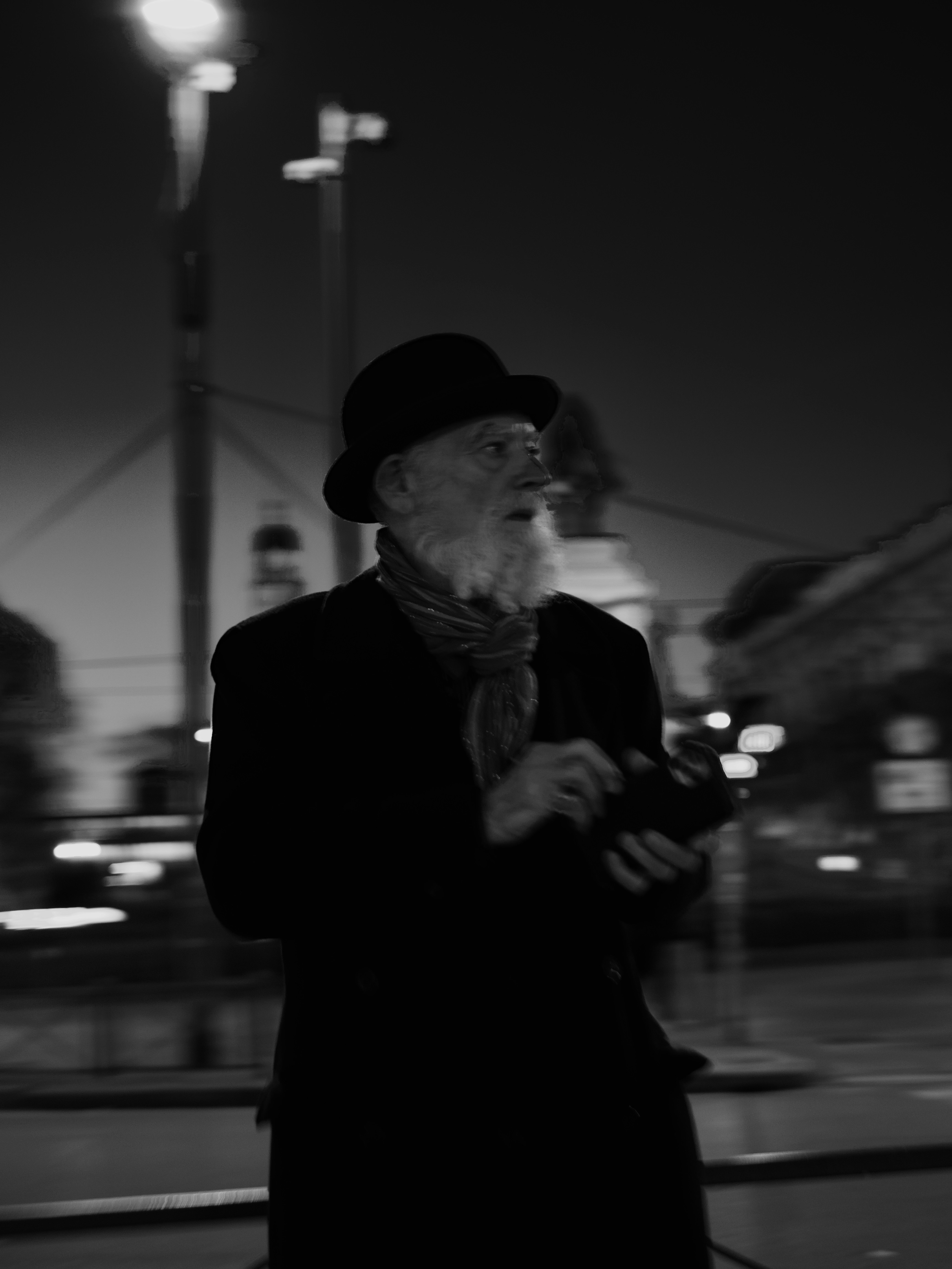 Nocturnal Blur: A hat-wearing man with a camera in a city at night