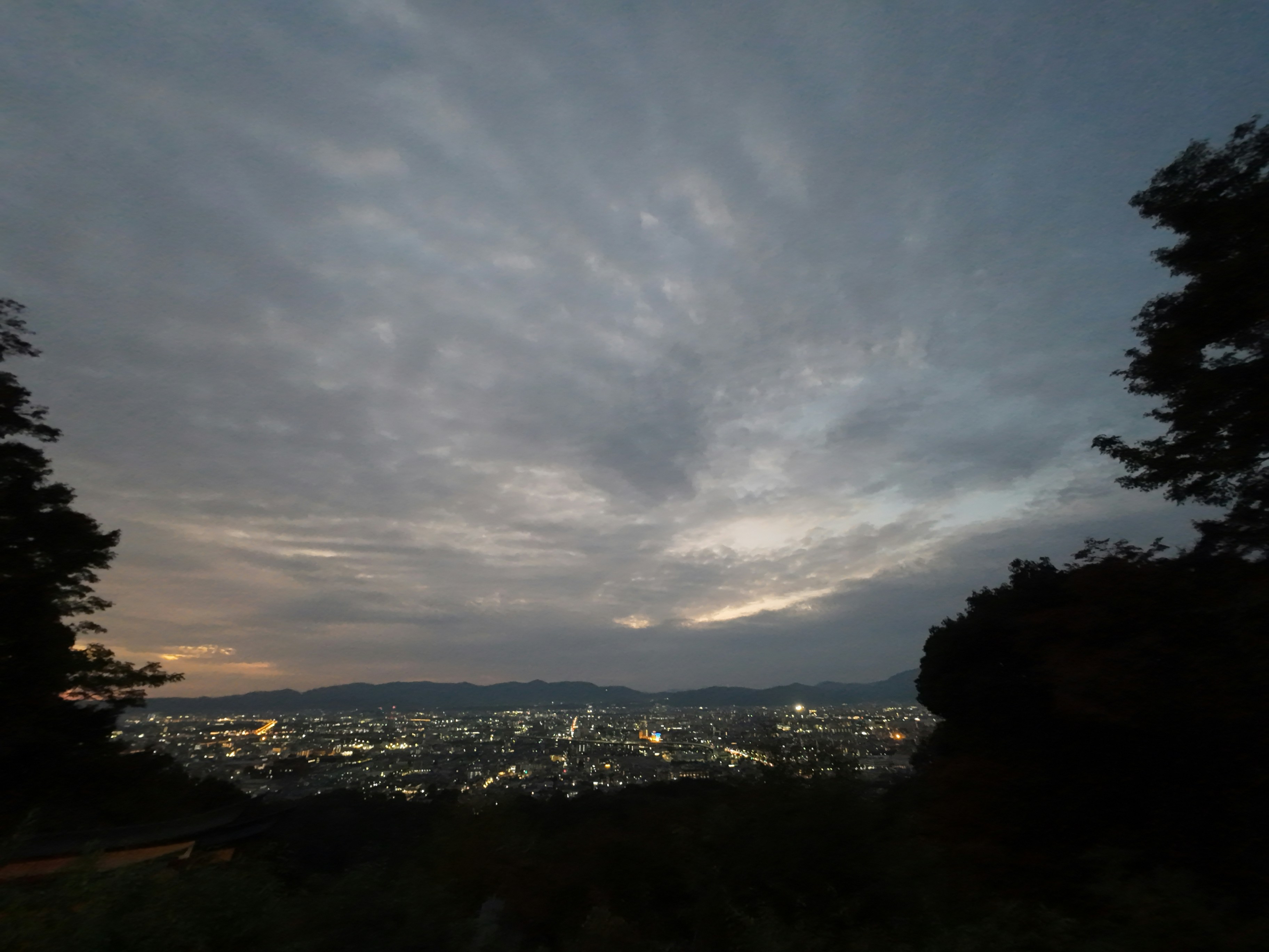 City lights twinkle under a cloudy twilight sky.