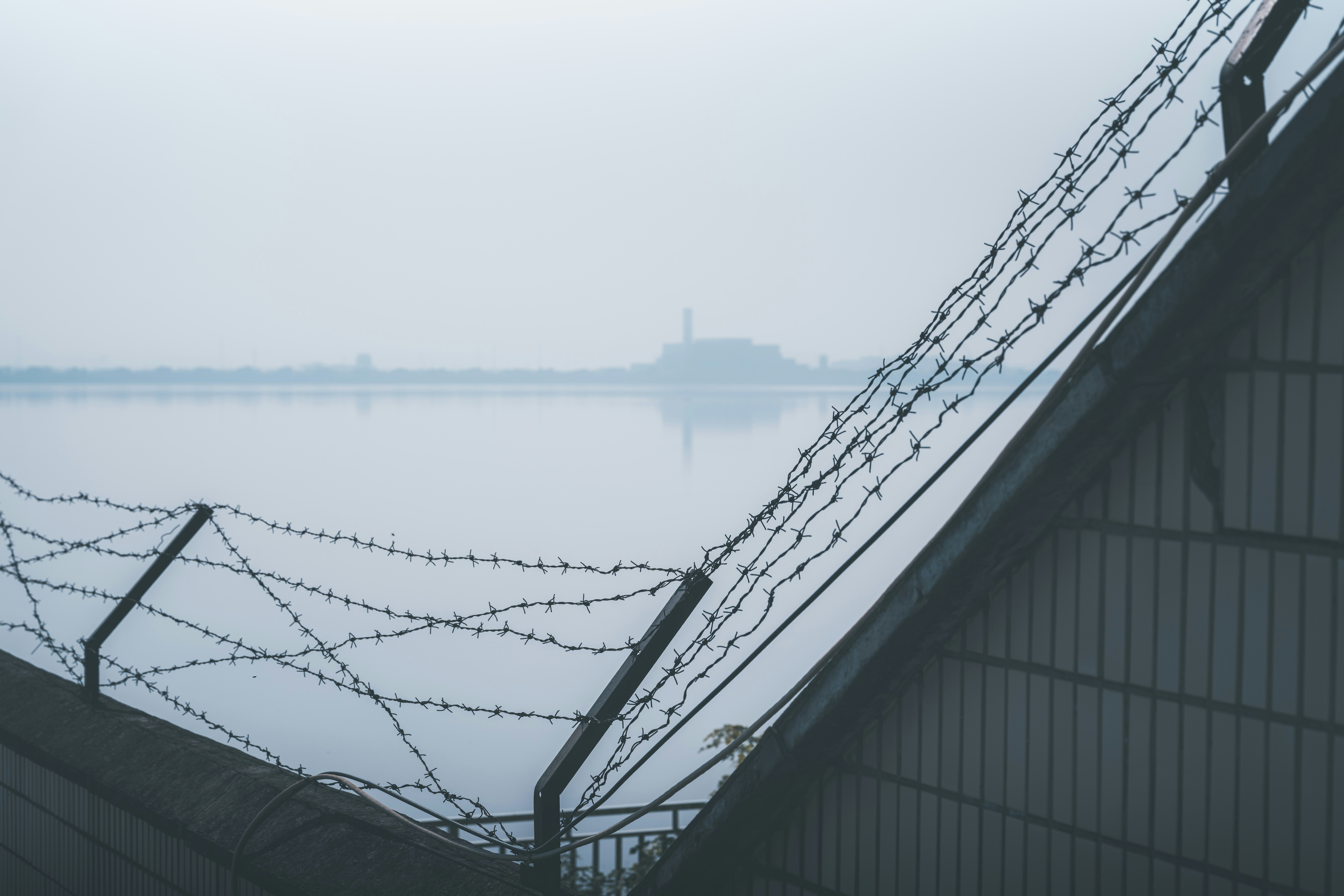 Barbed Horizon Over a Misty Waterfront