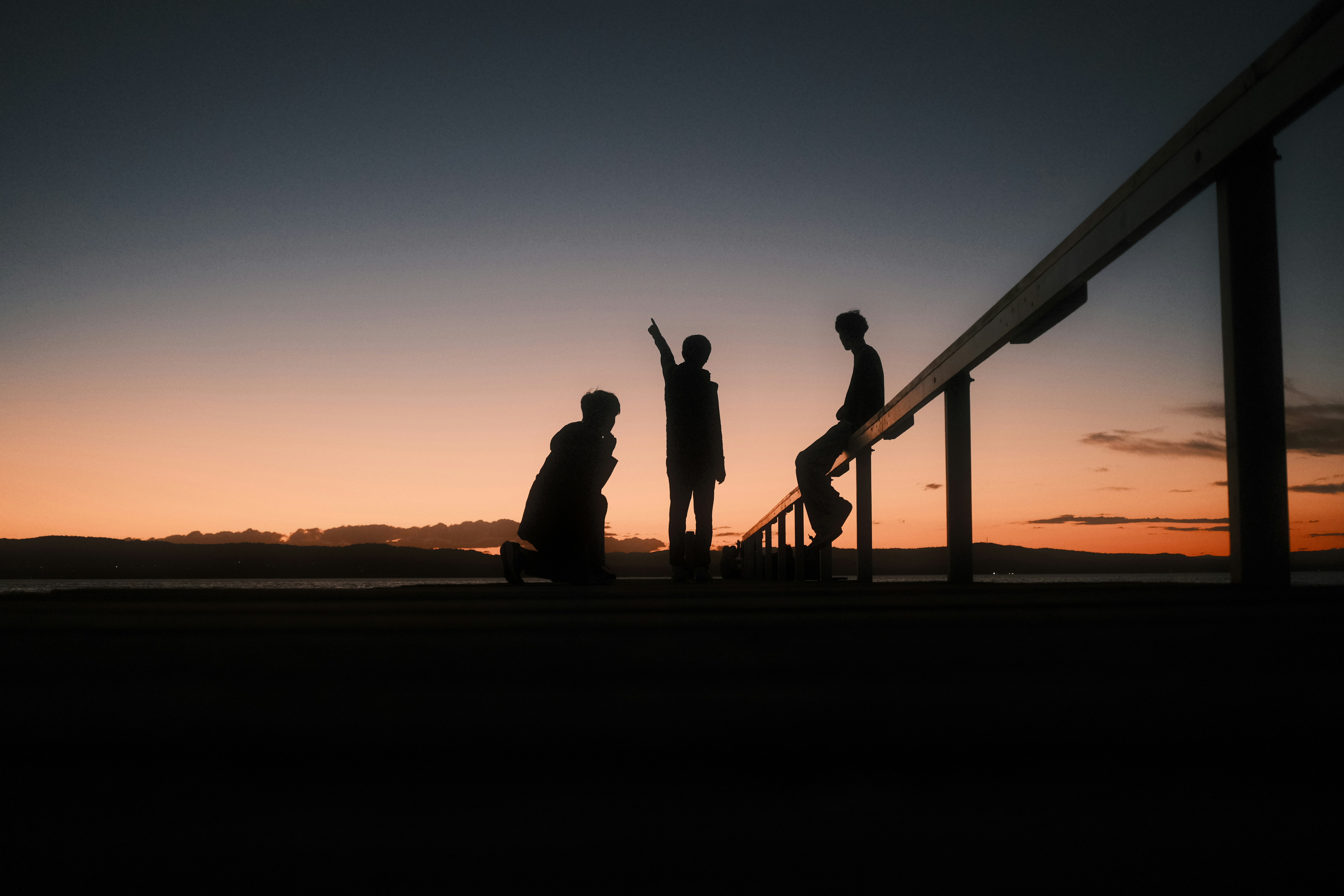 Dusk on the Pier: Four Silhouettes Beneath a Sunset Sky