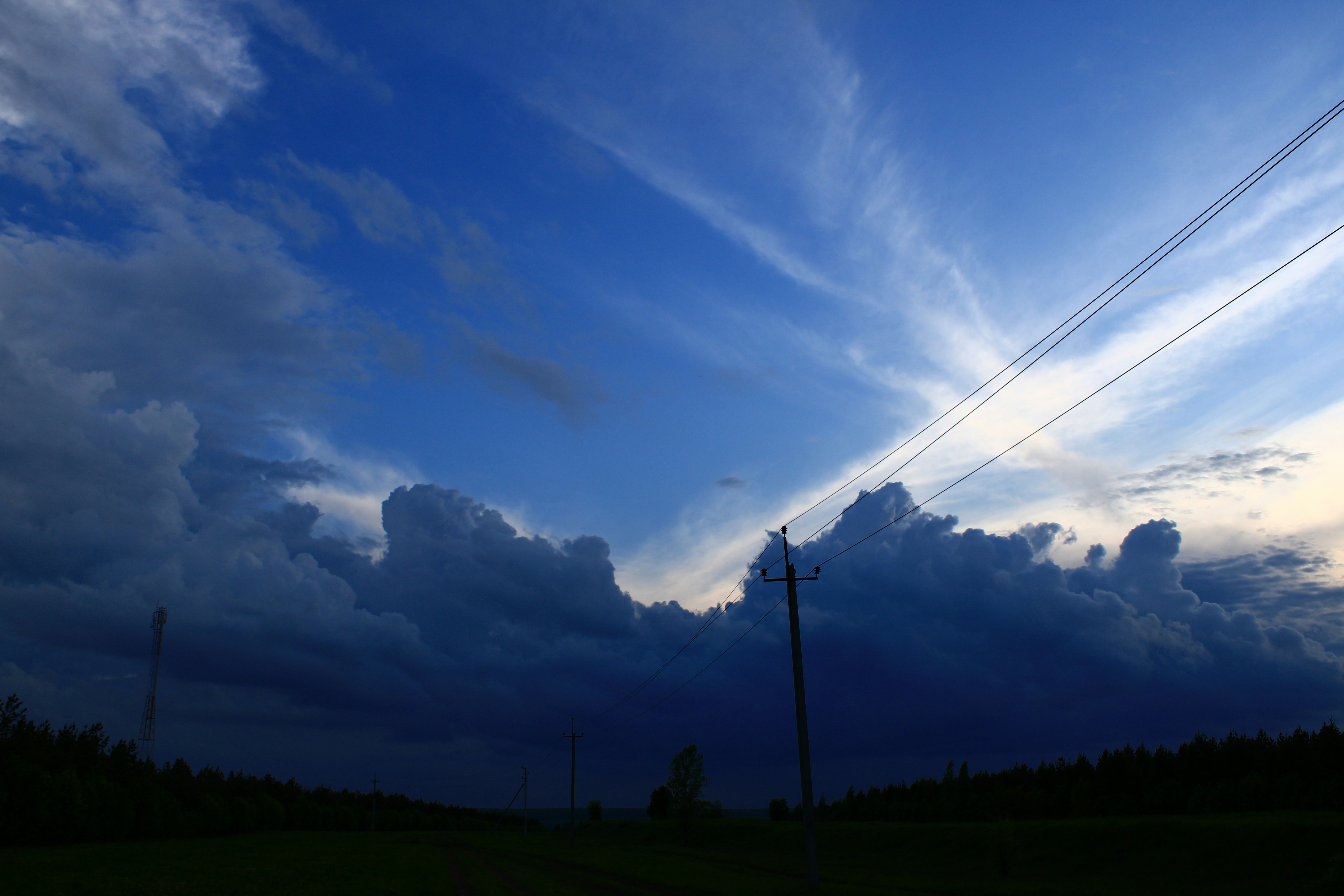 Storm Looms Over a Quiet Field, Framed by a Lone Power Line