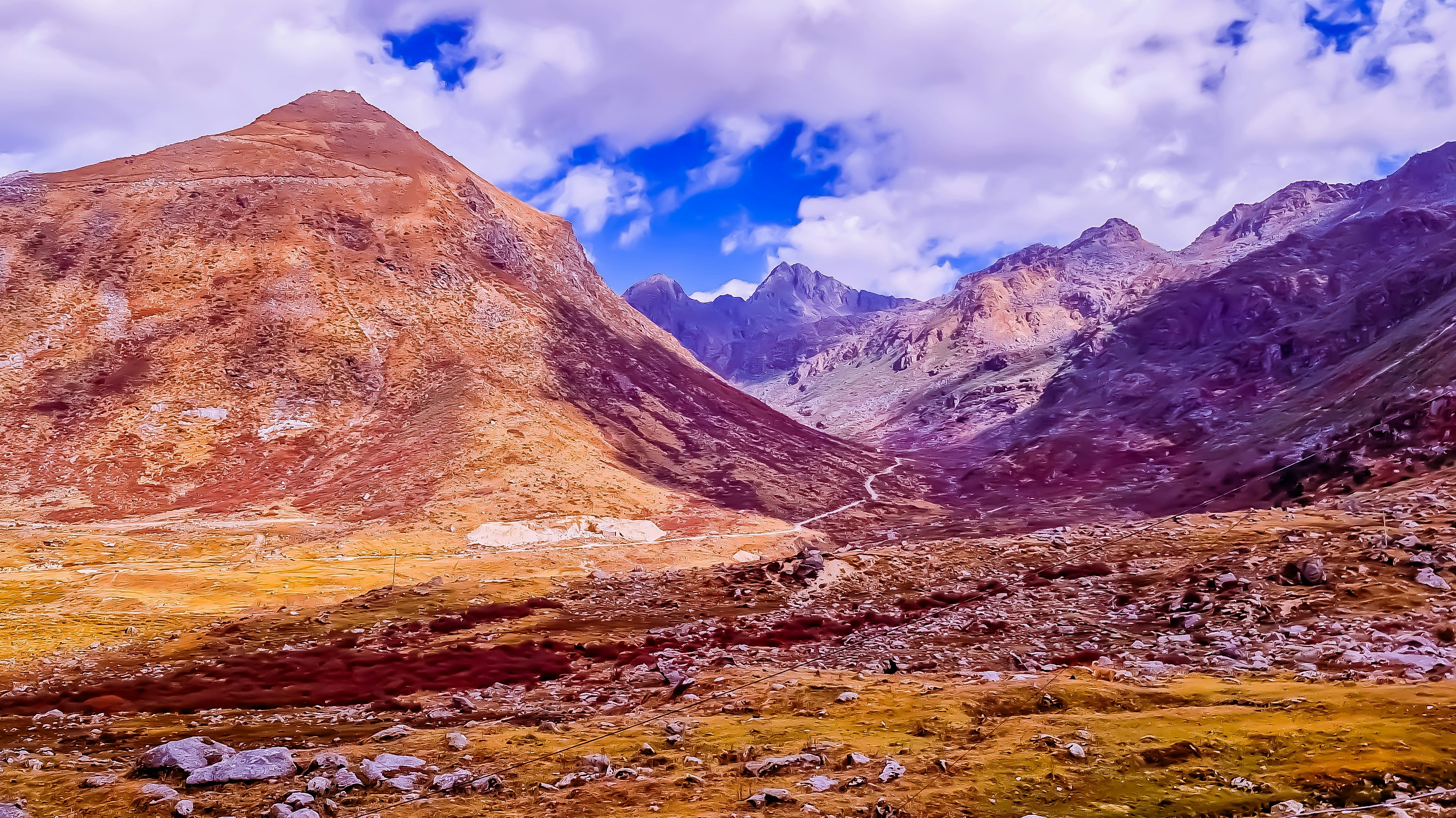 Rugged mountain landscape with colorful sky and dry grass.