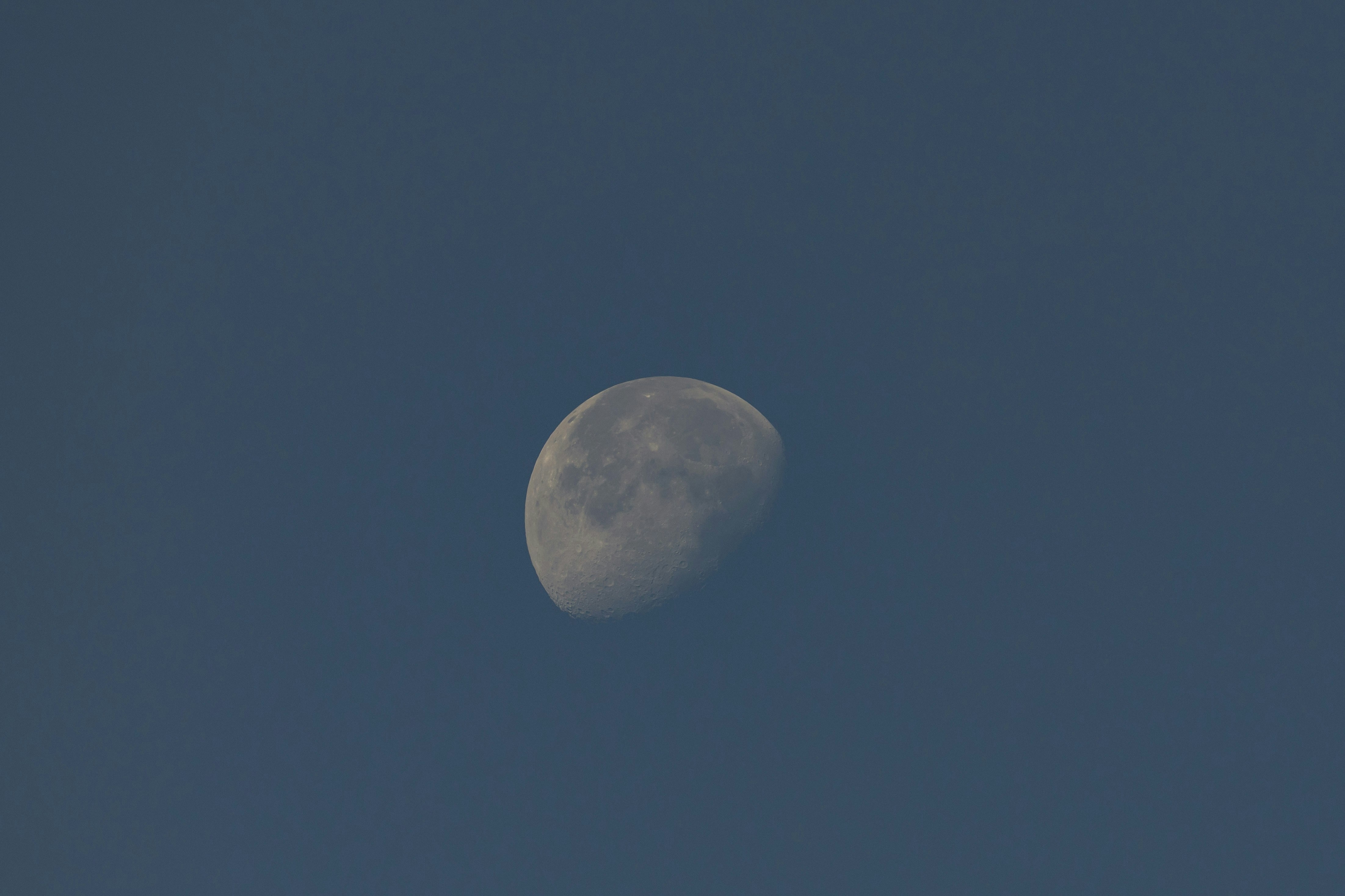 A waxing gibbous moon in a clear blue sky