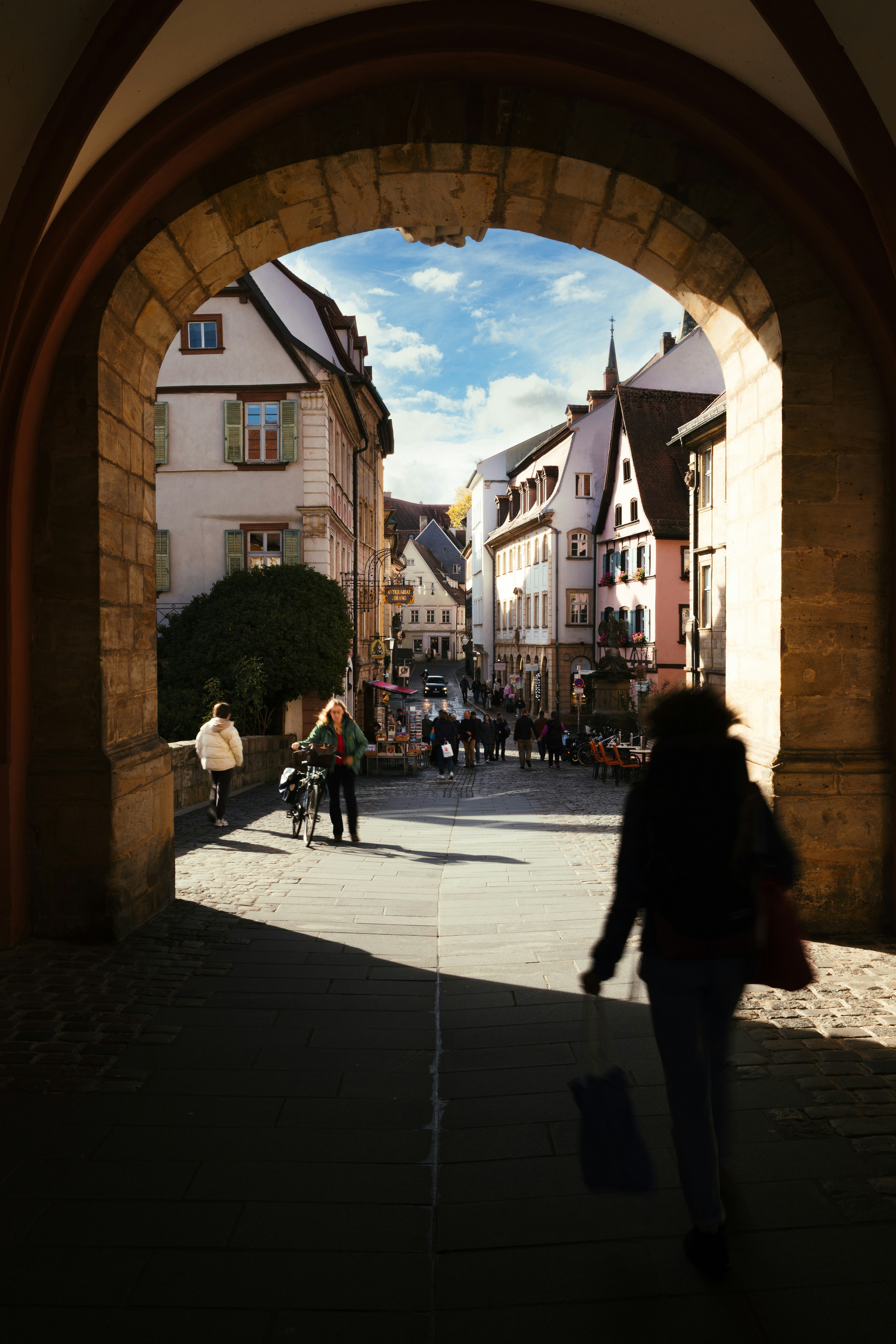 Through the Arch, a Sunlit European Street Comes Alive