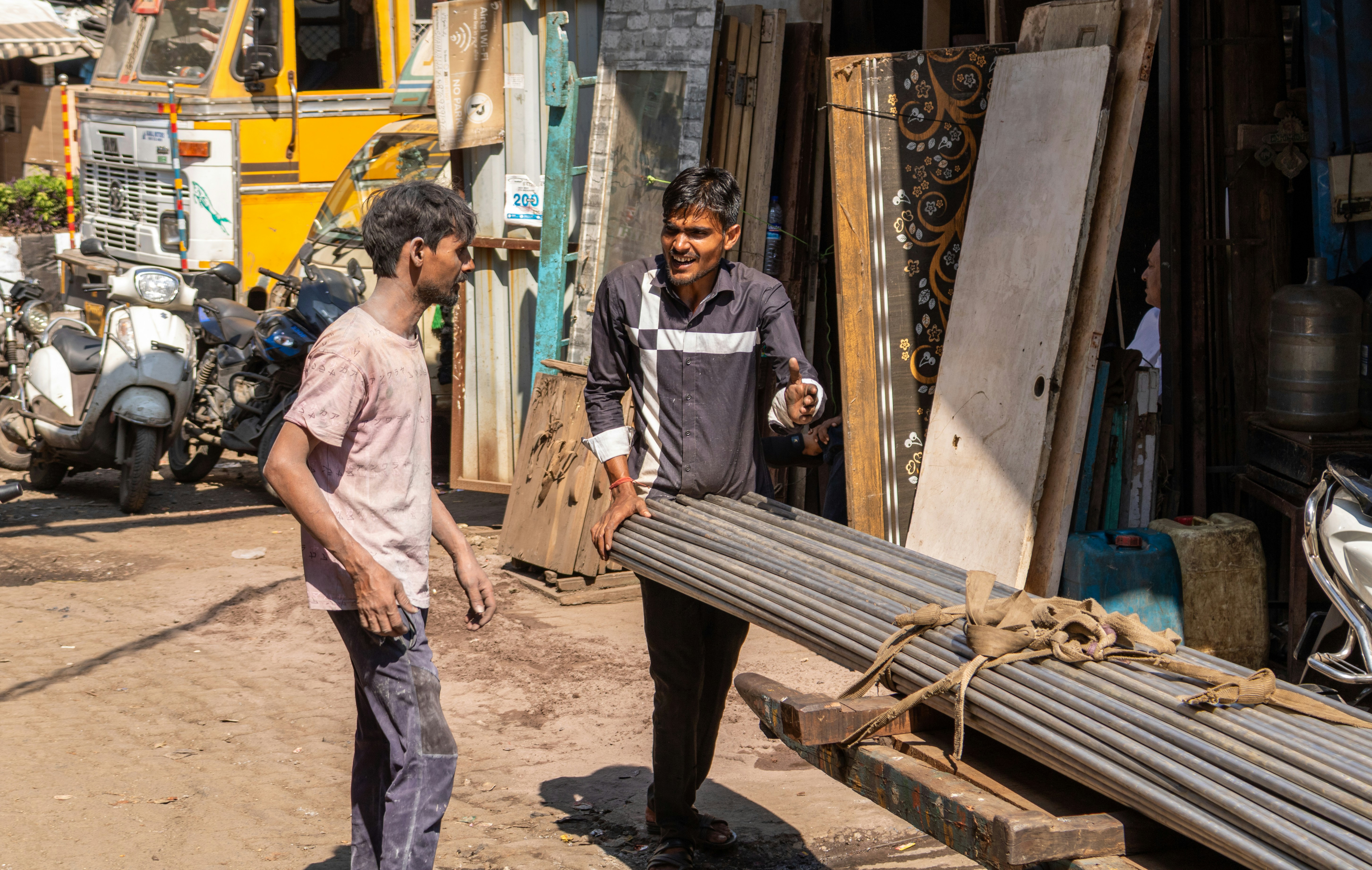 Two men carrying metal pipes on a street. photo – Free City Image on ...
