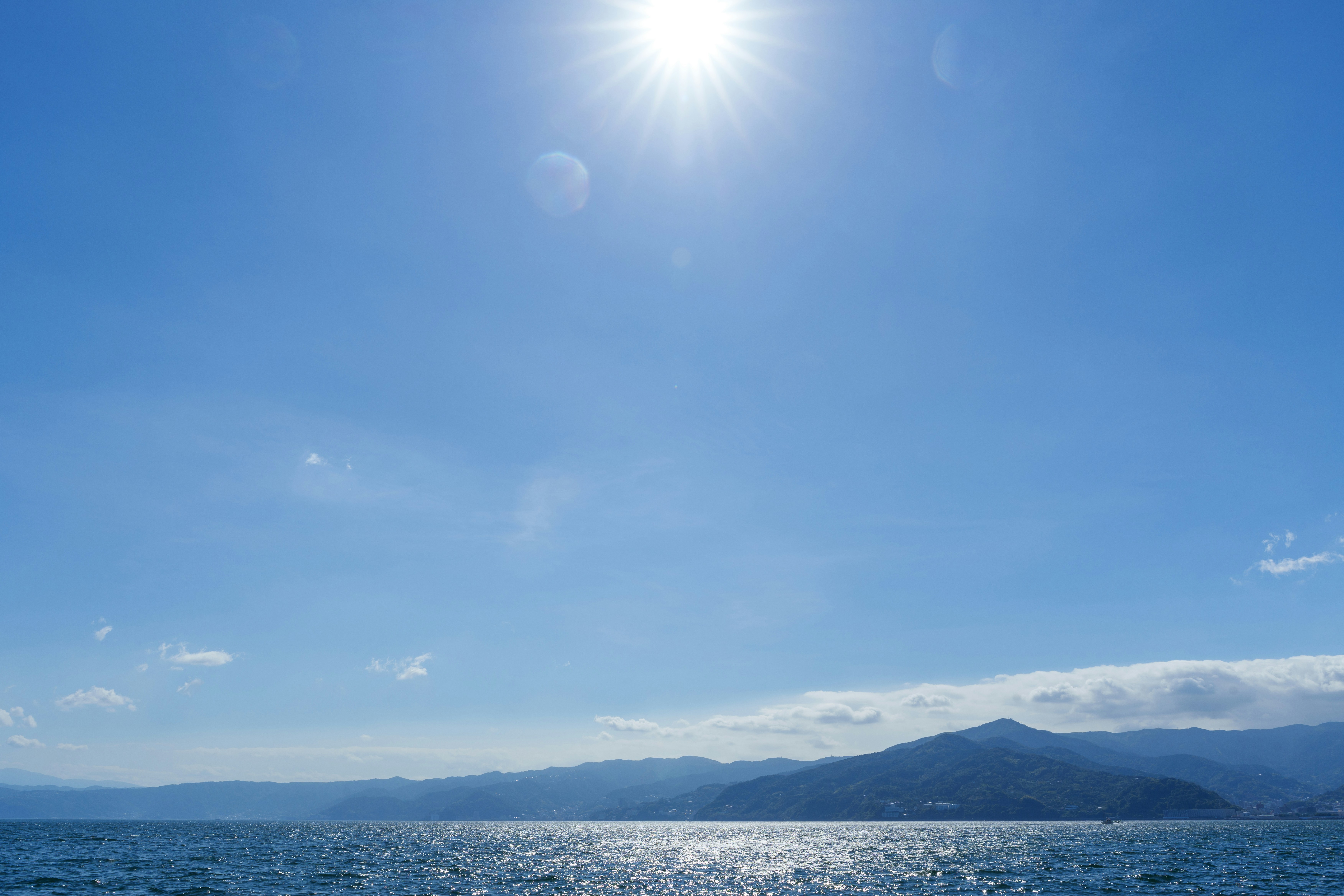 Bright sun shines over blue ocean and distant mountains. photo – Free ...