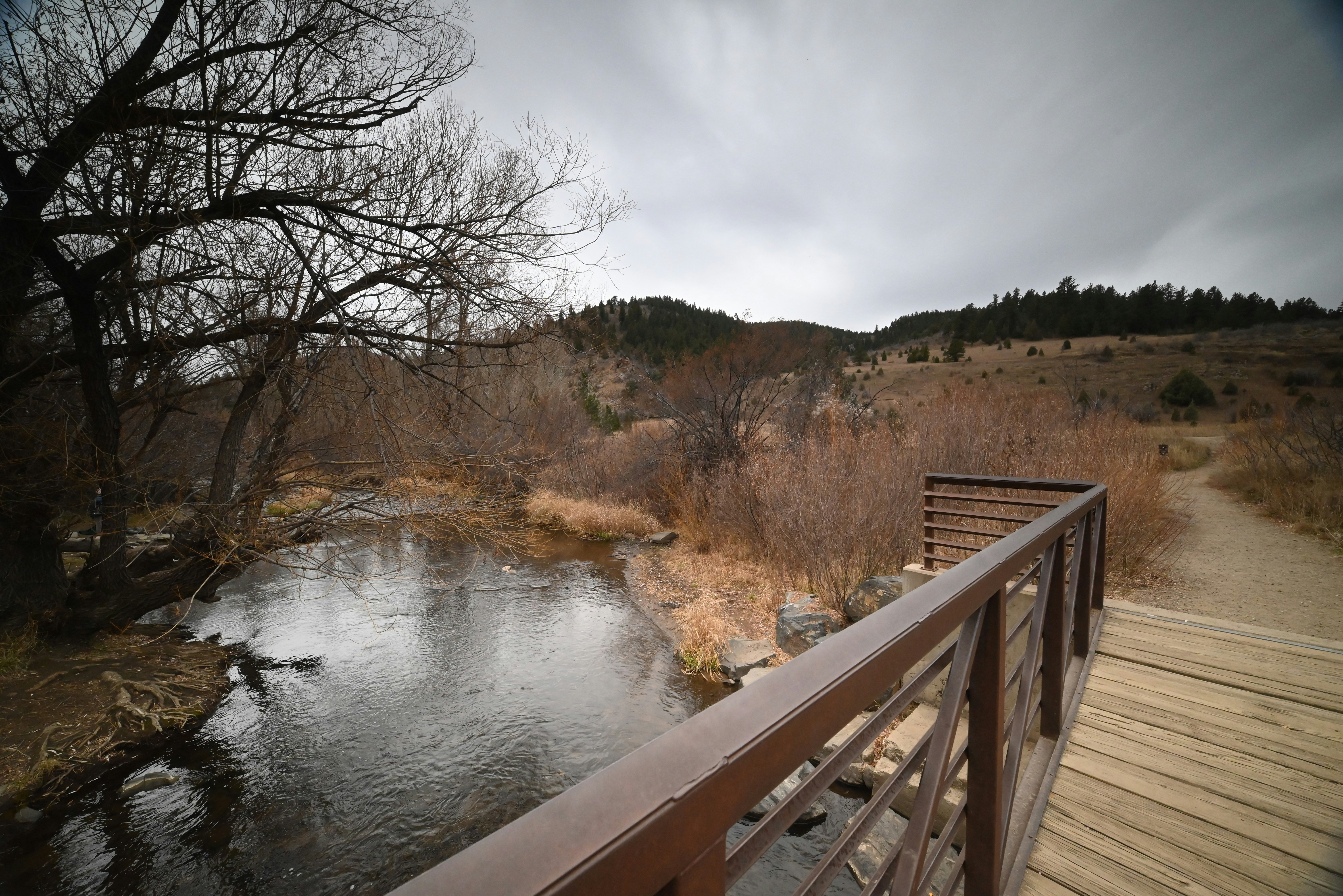 Railing into the Quiet: a wooden bridge over a sleepy river in late autumn